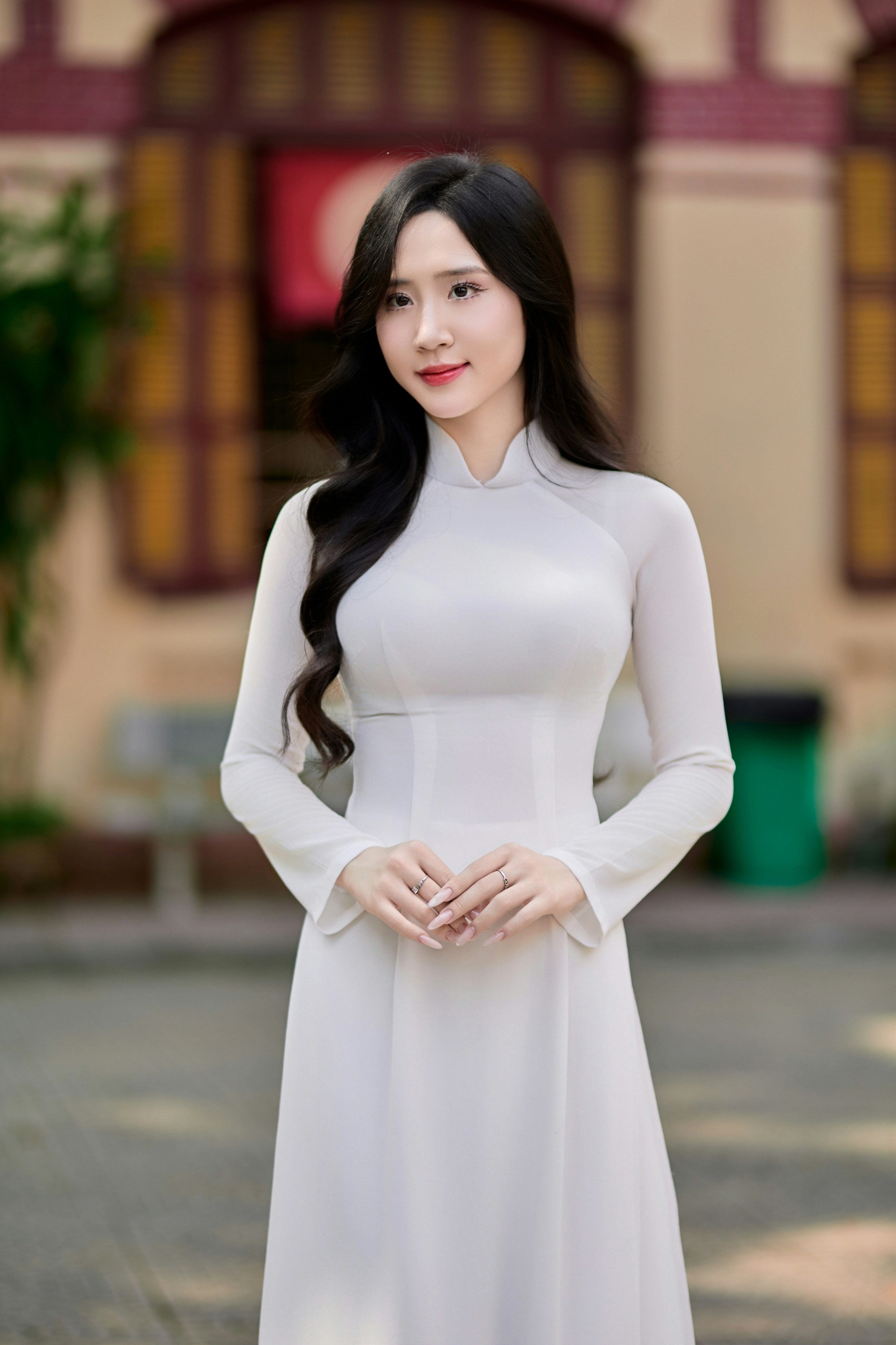 A young woman in a flowing white ao dai stands gracefully, embodying cultural elegance against a softly blurred background.
