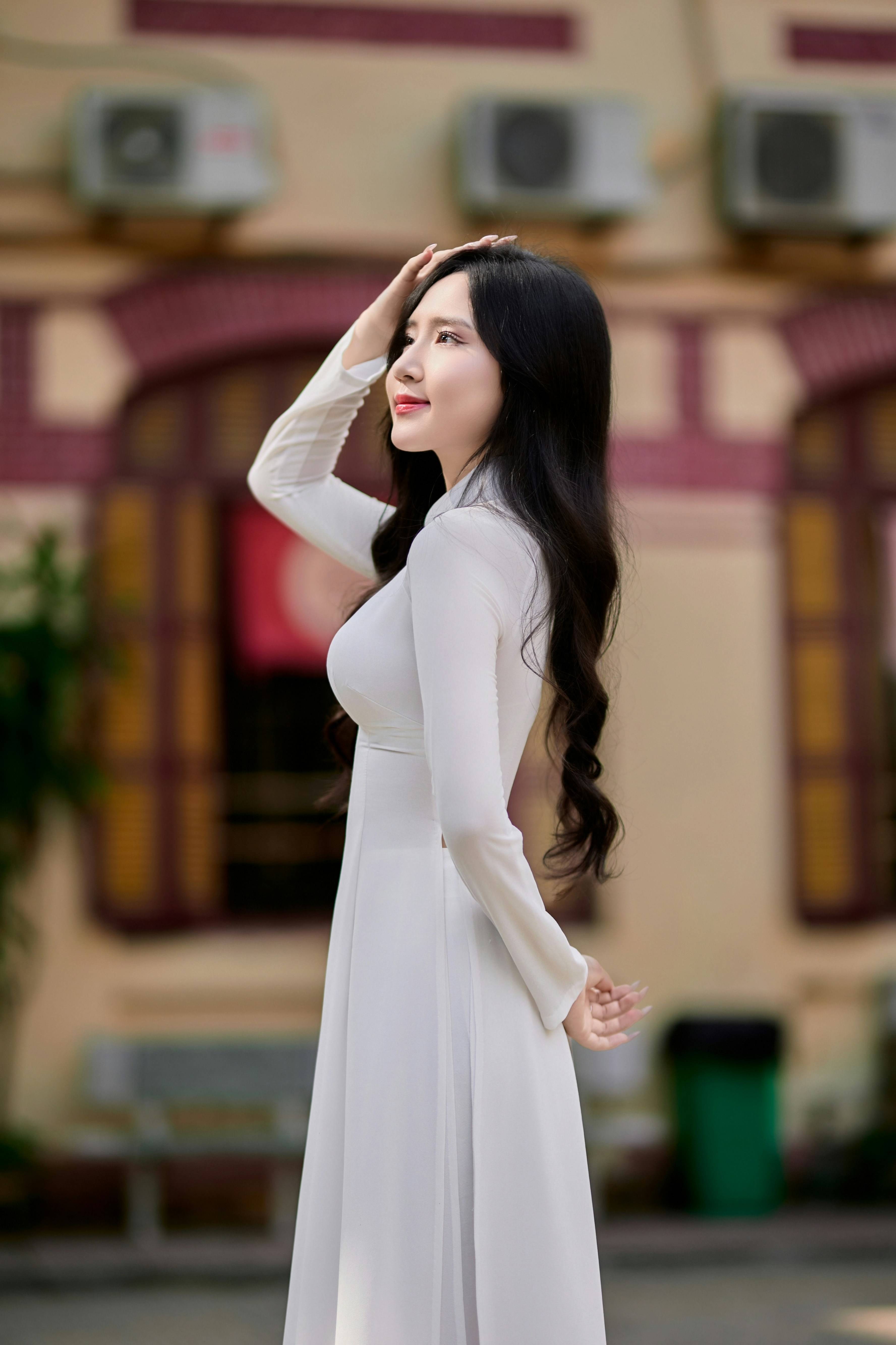 Grace and timeless beauty in Vietnamese traditional dress | A woman in a white dress stands outdoors.