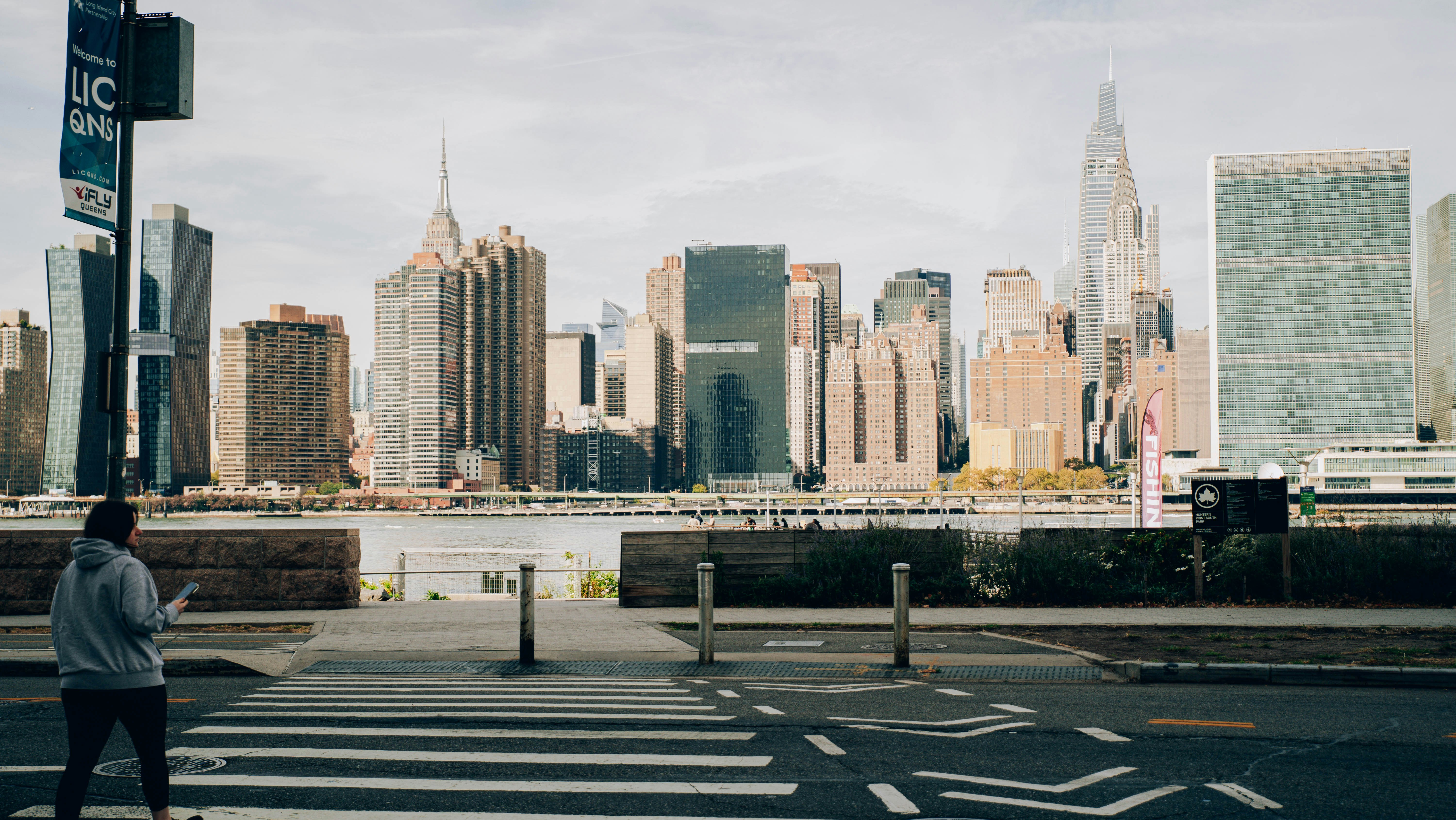 Gantry Plaza | Man walking across street with city skyline behind