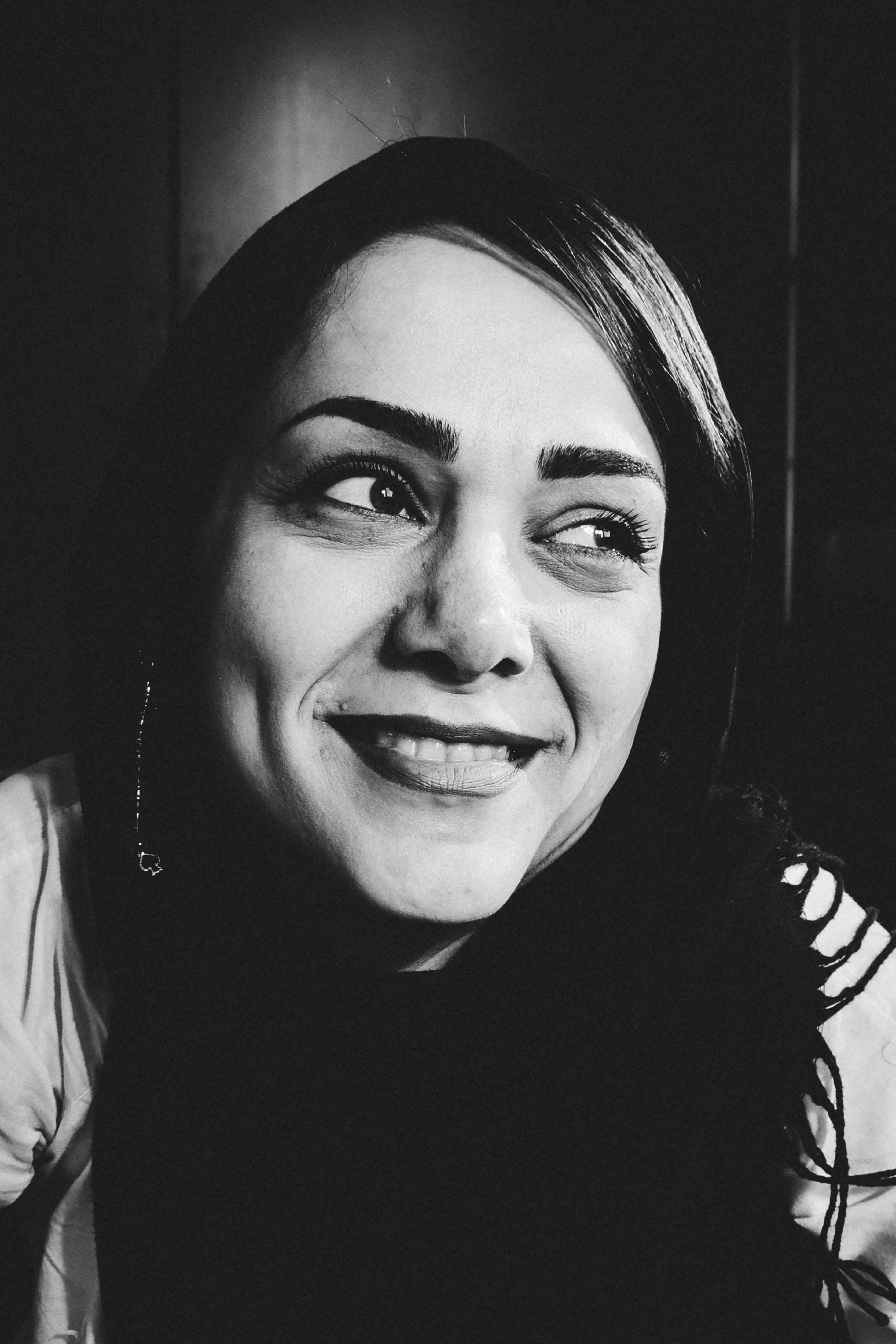 A smiling woman with dark hair looks away.