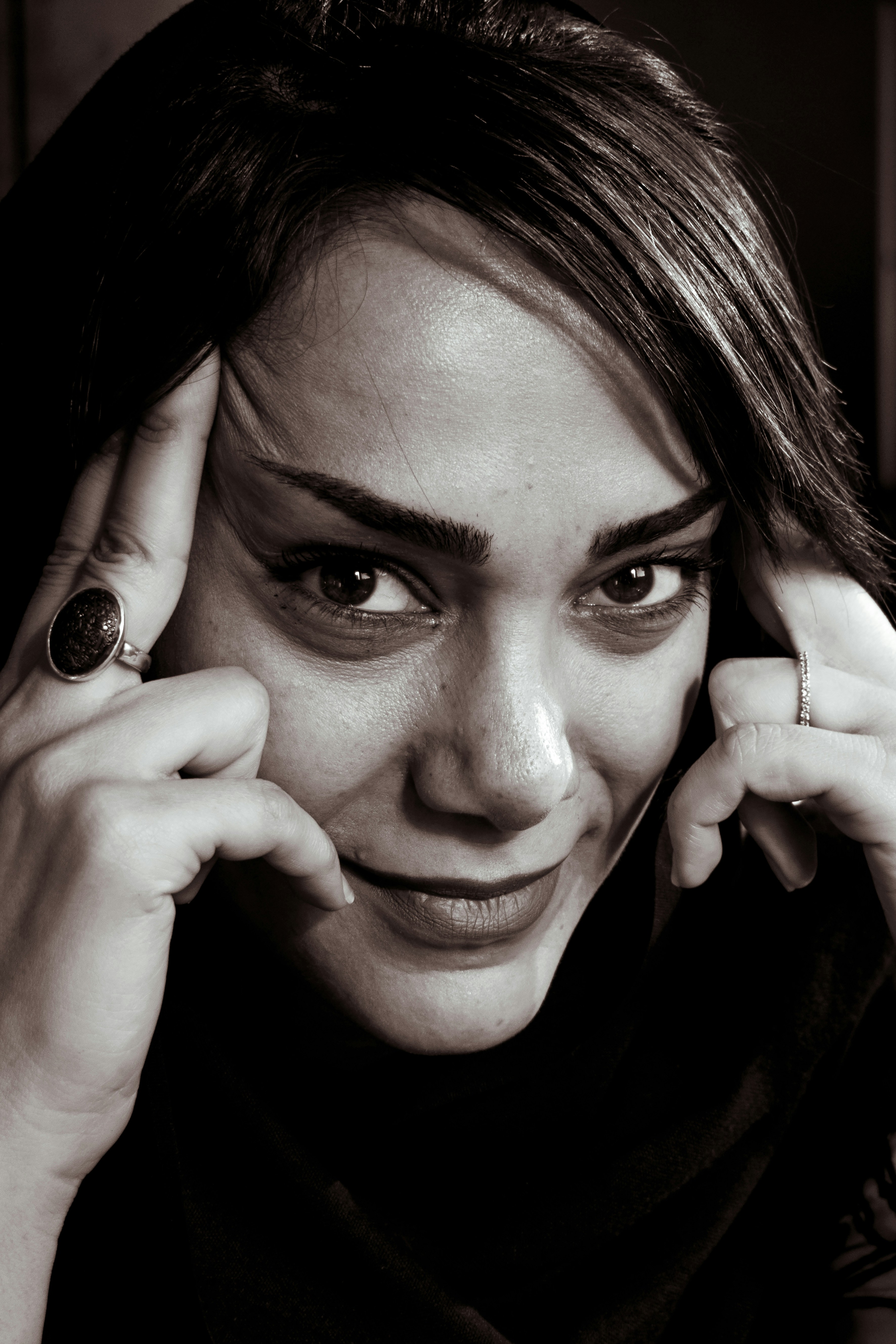 A woman with hands on her temples smiles