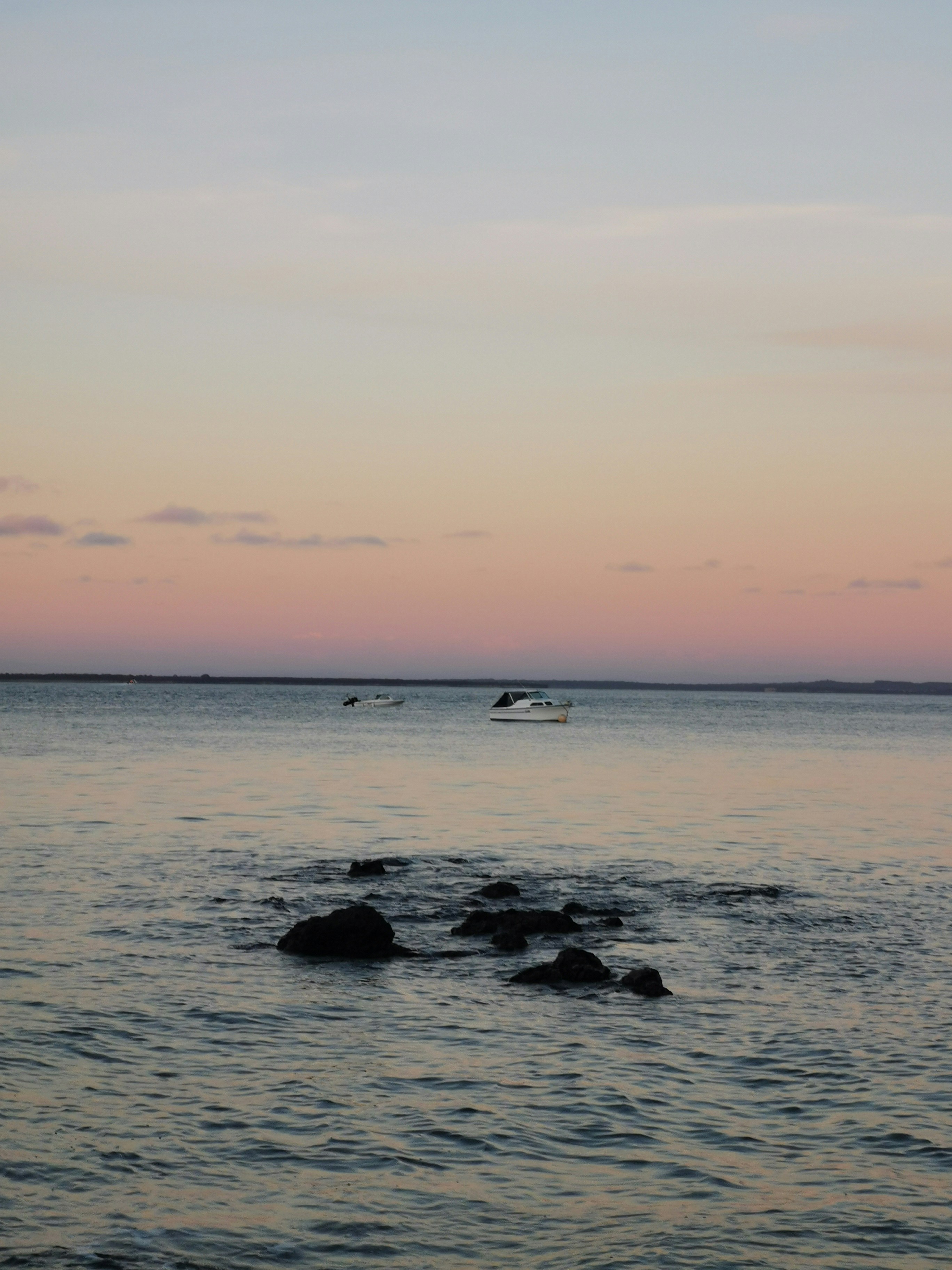 Boats on the water at sunset with rocks