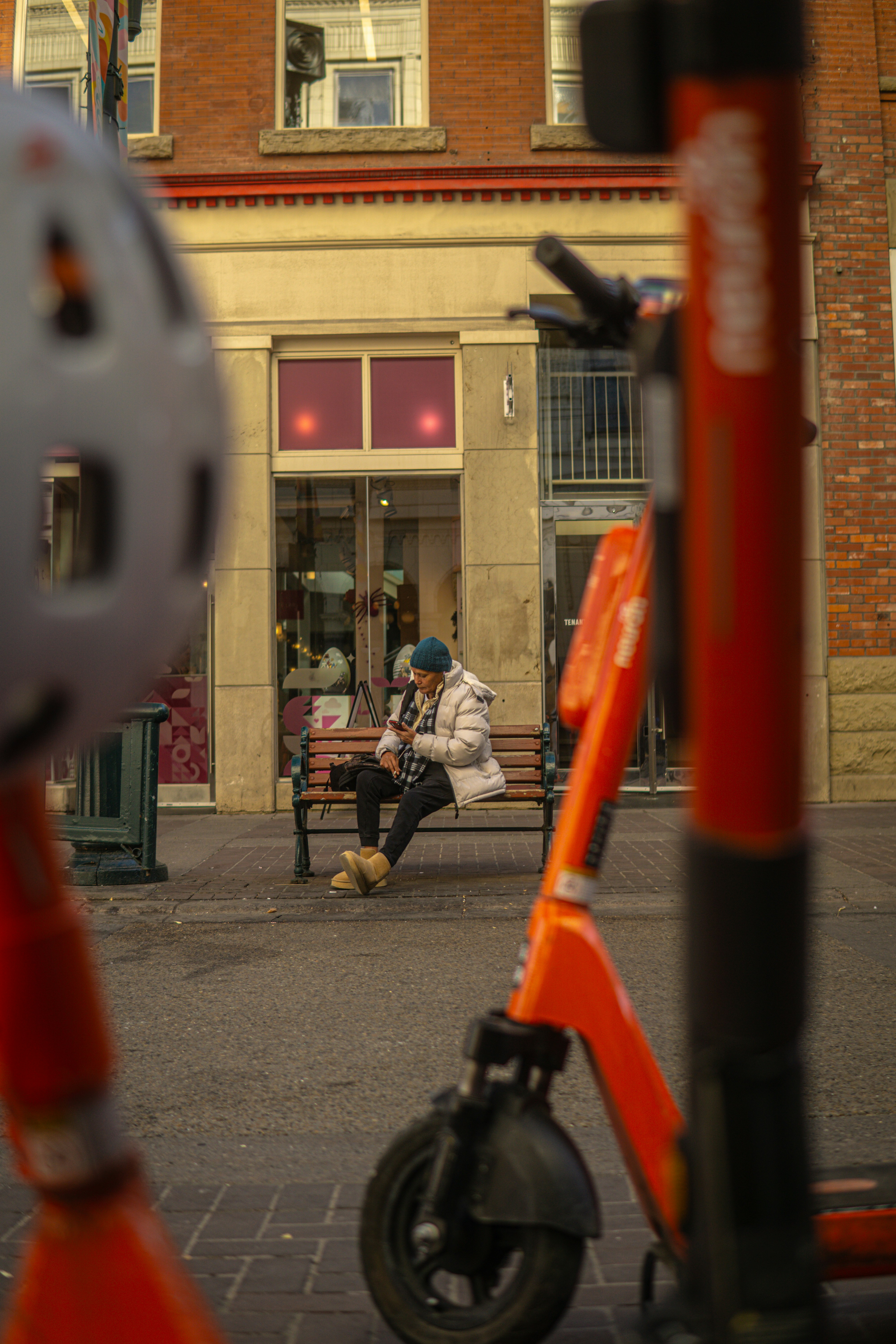 Urban Pause: A lone figure on a bench framed by orange city machinery