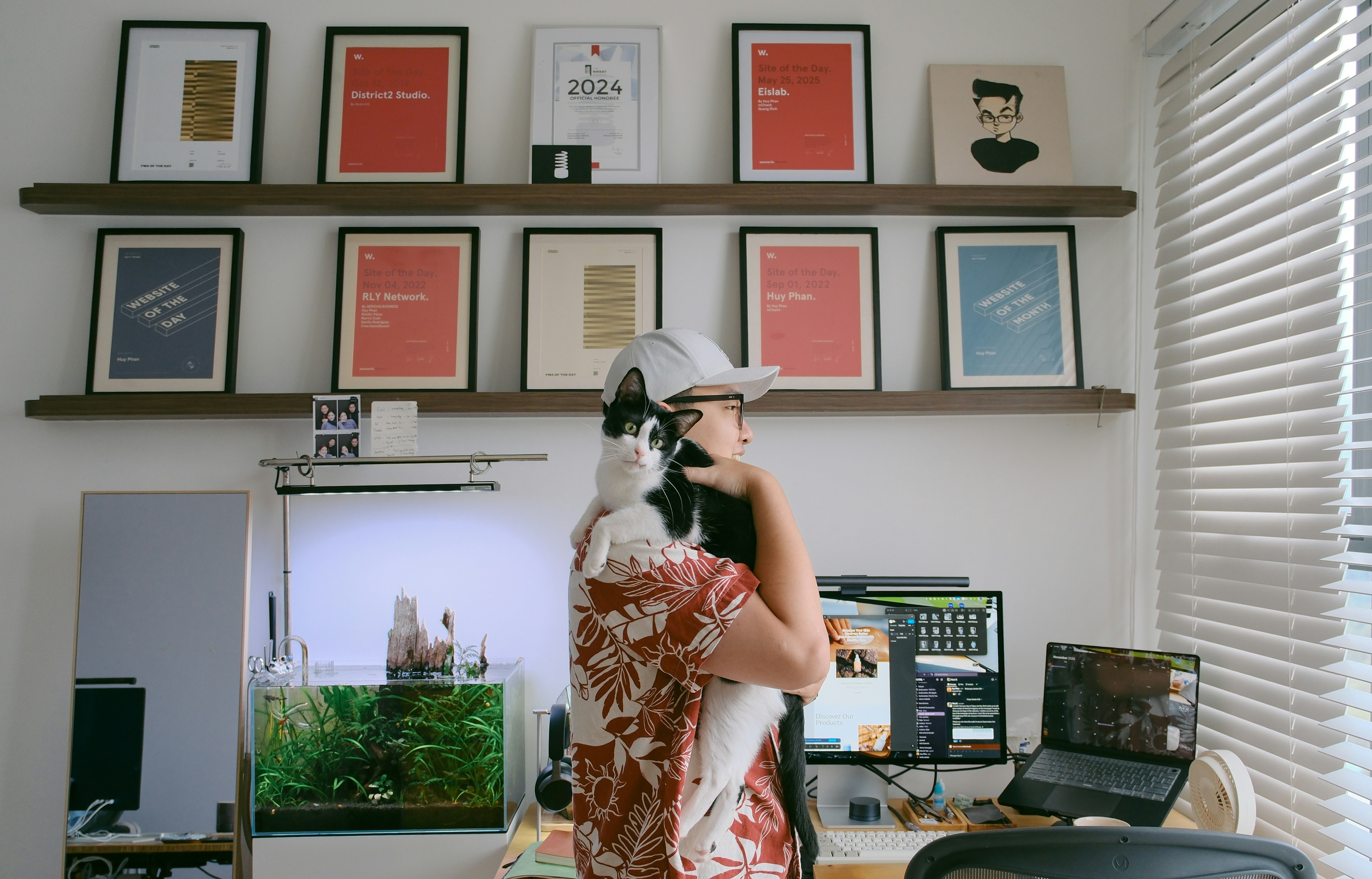 Person holding a cat in a room with shelves.