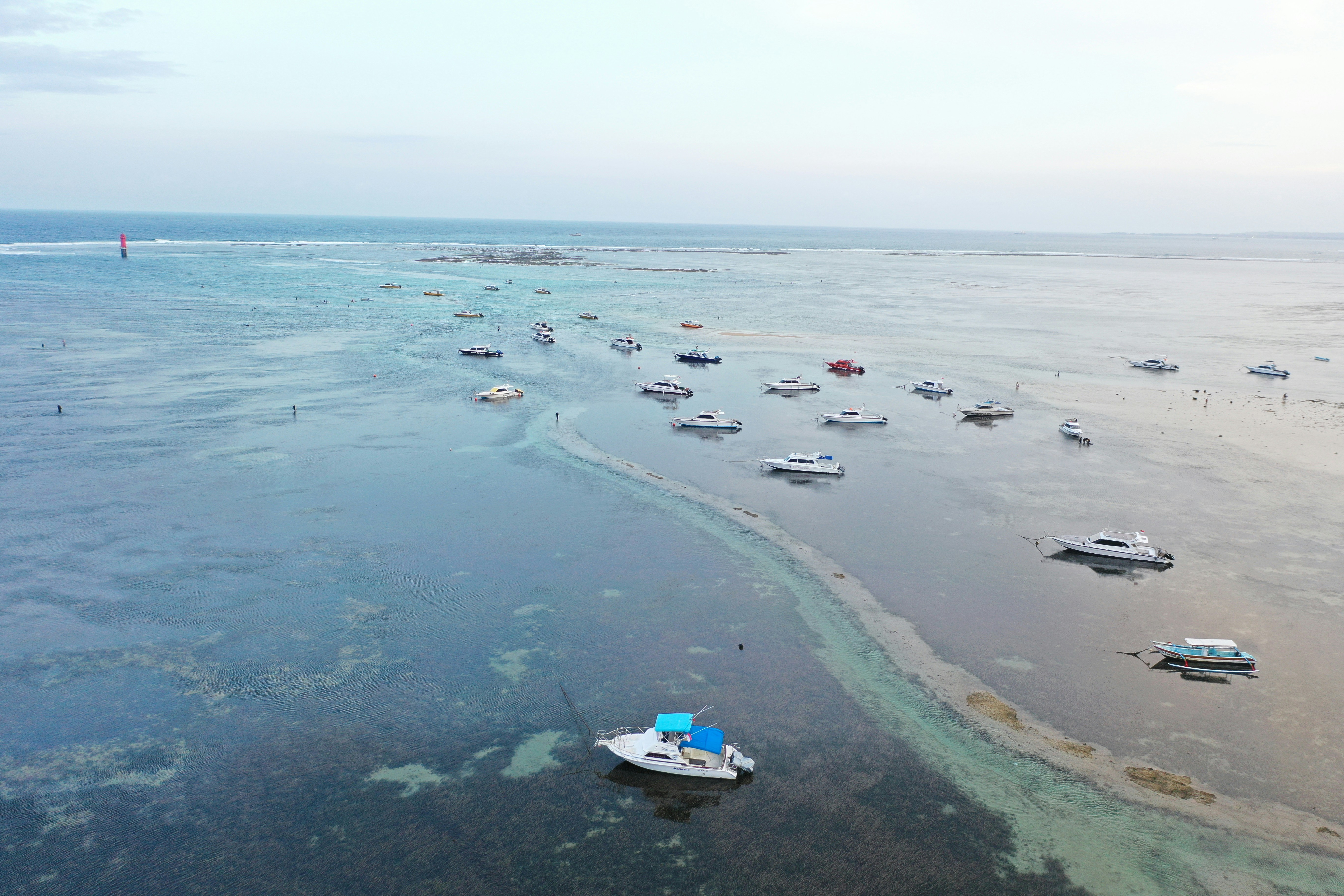 Many boats anchored in shallow, clear tropical water.