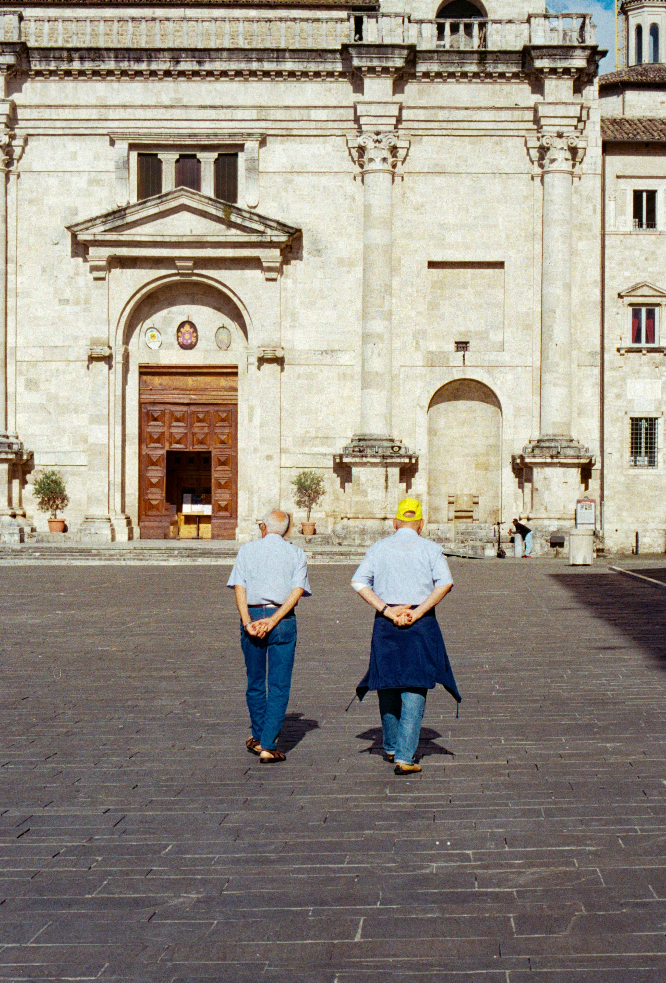 Two people walking towards a large building entrance.