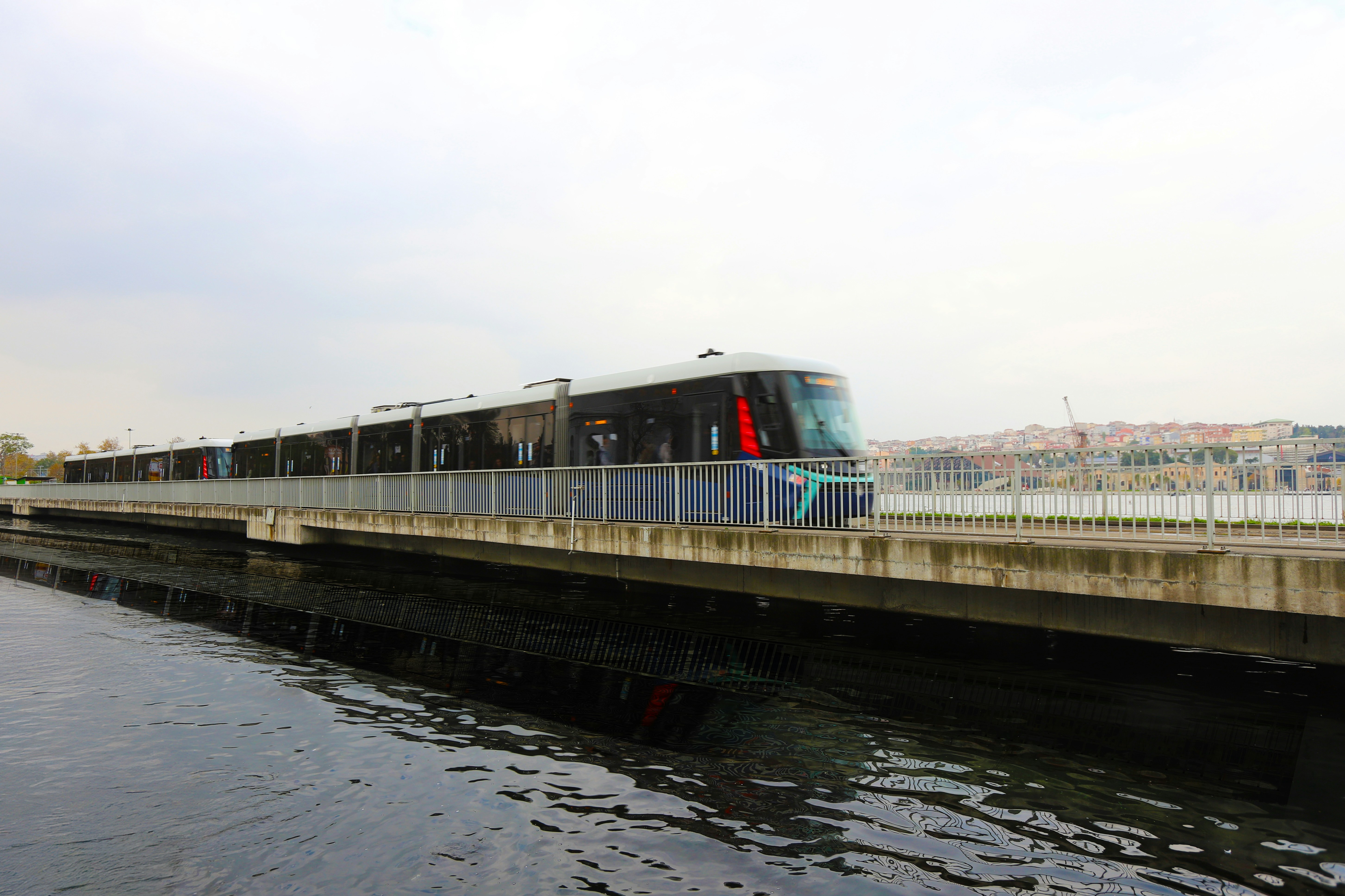 A modern train travels on a bridge over water.