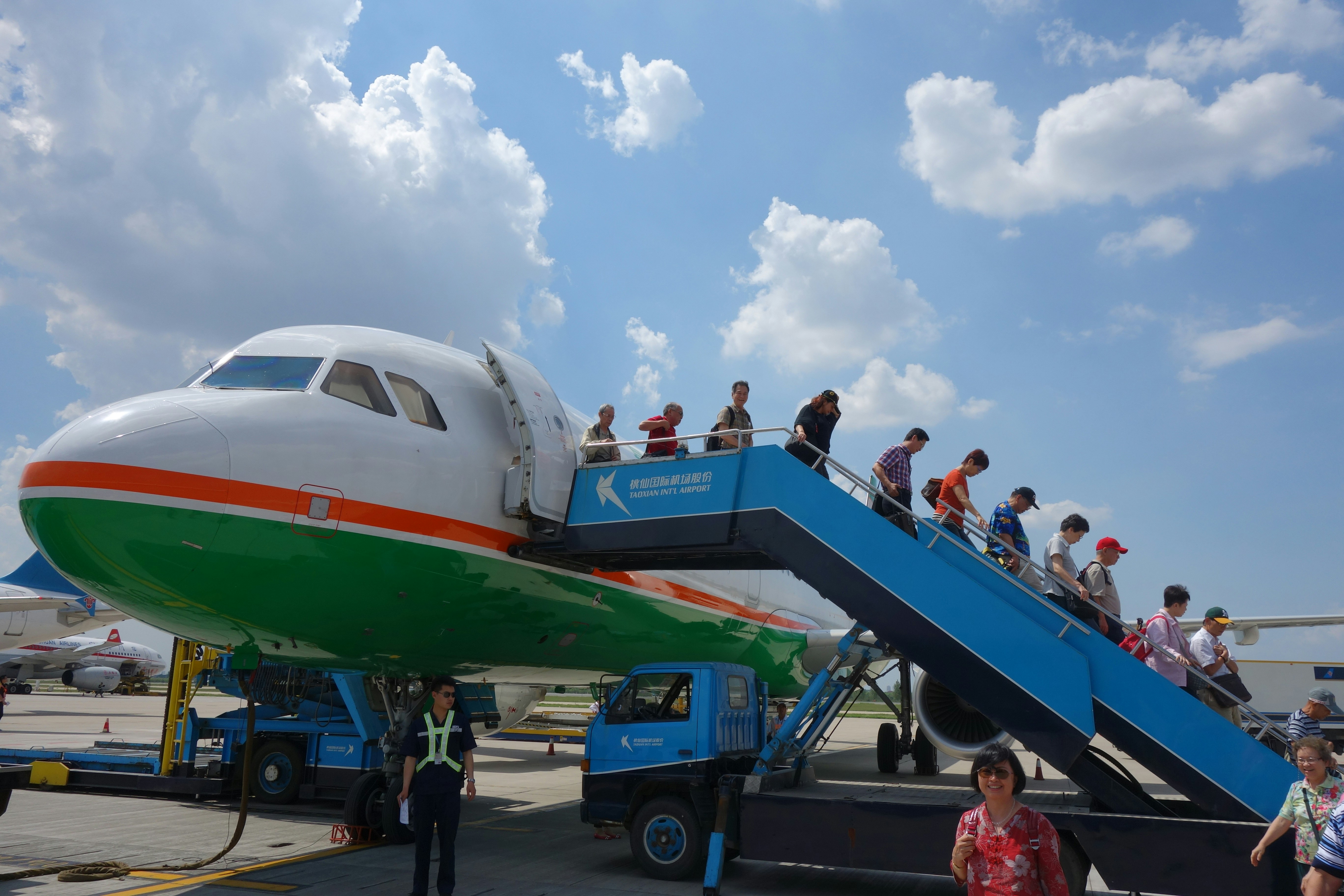 Passengers boarding an airplane on a sunny day.