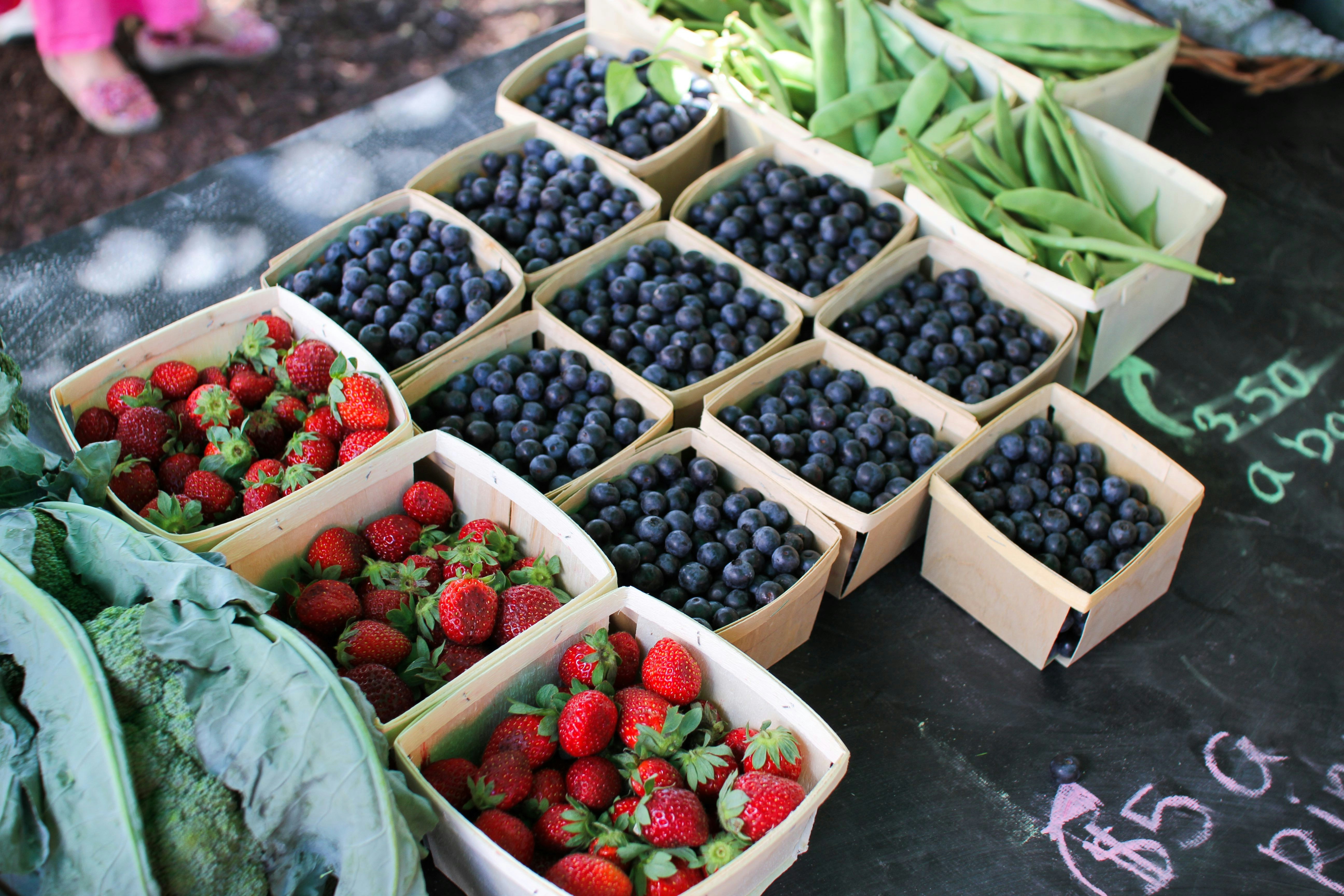 Fresh strawberries, blueberries, and peas at a market.