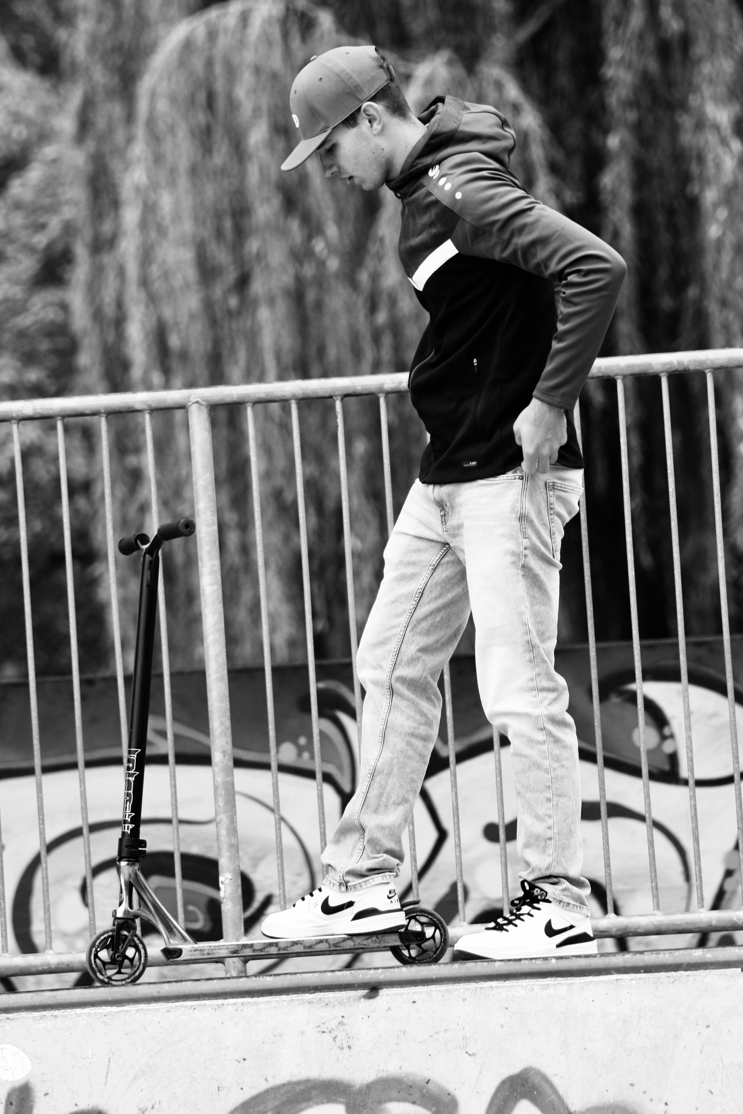 Style trifft auf Sport | Young man with scooter on a railing