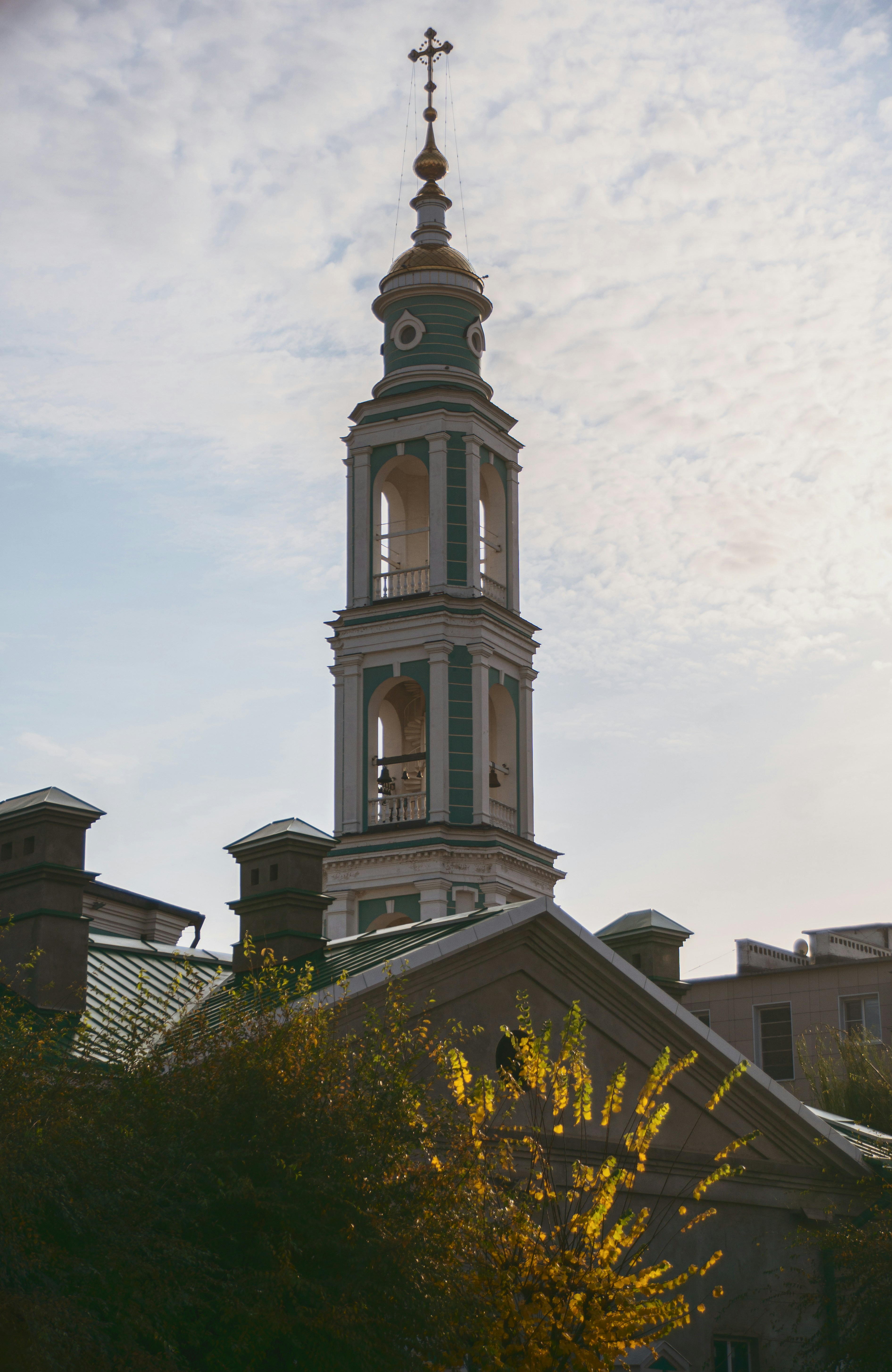 Verdant Bell Tower Rising Over a Sunlit Rooftop