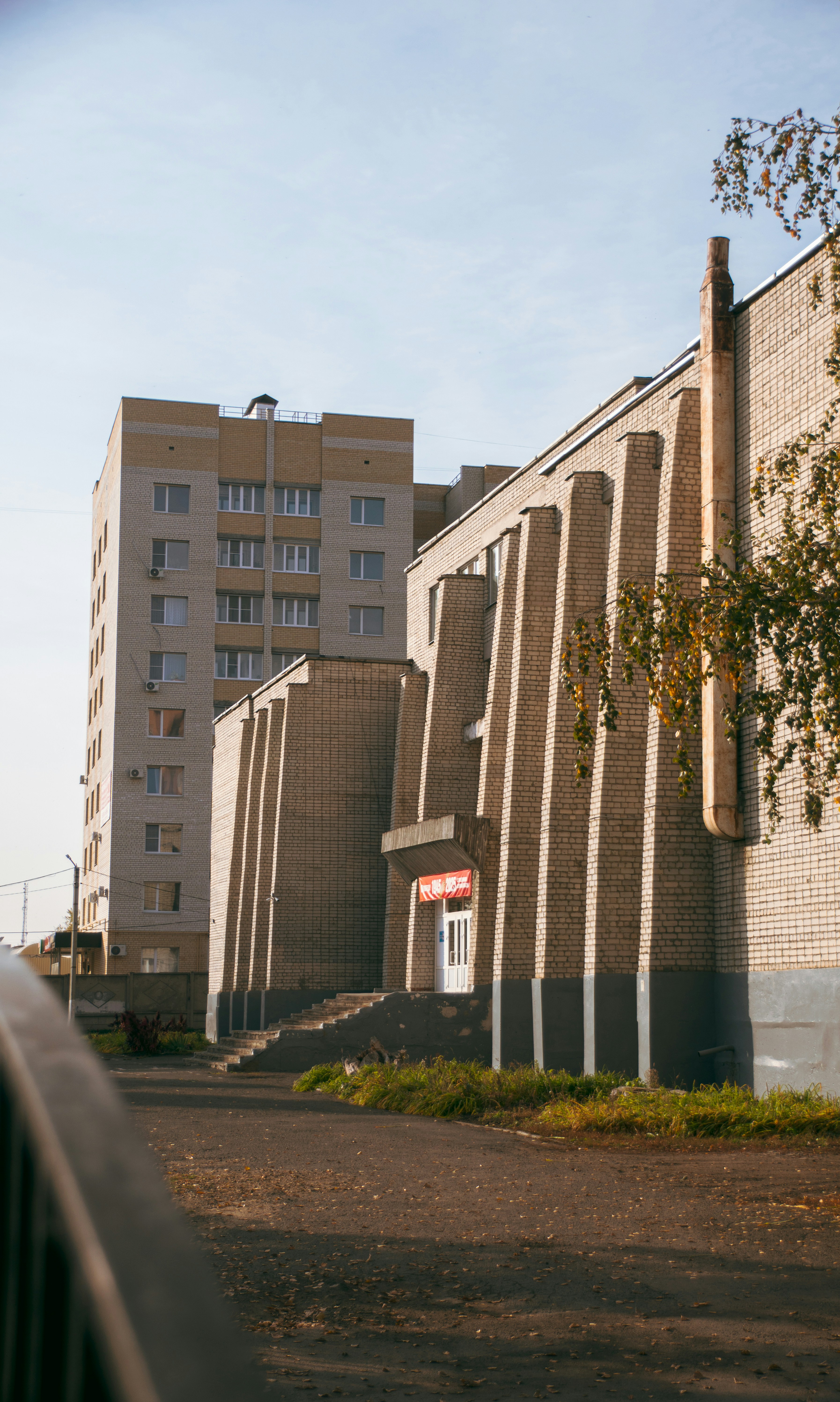 Brick building with modern apartment complex behind it.