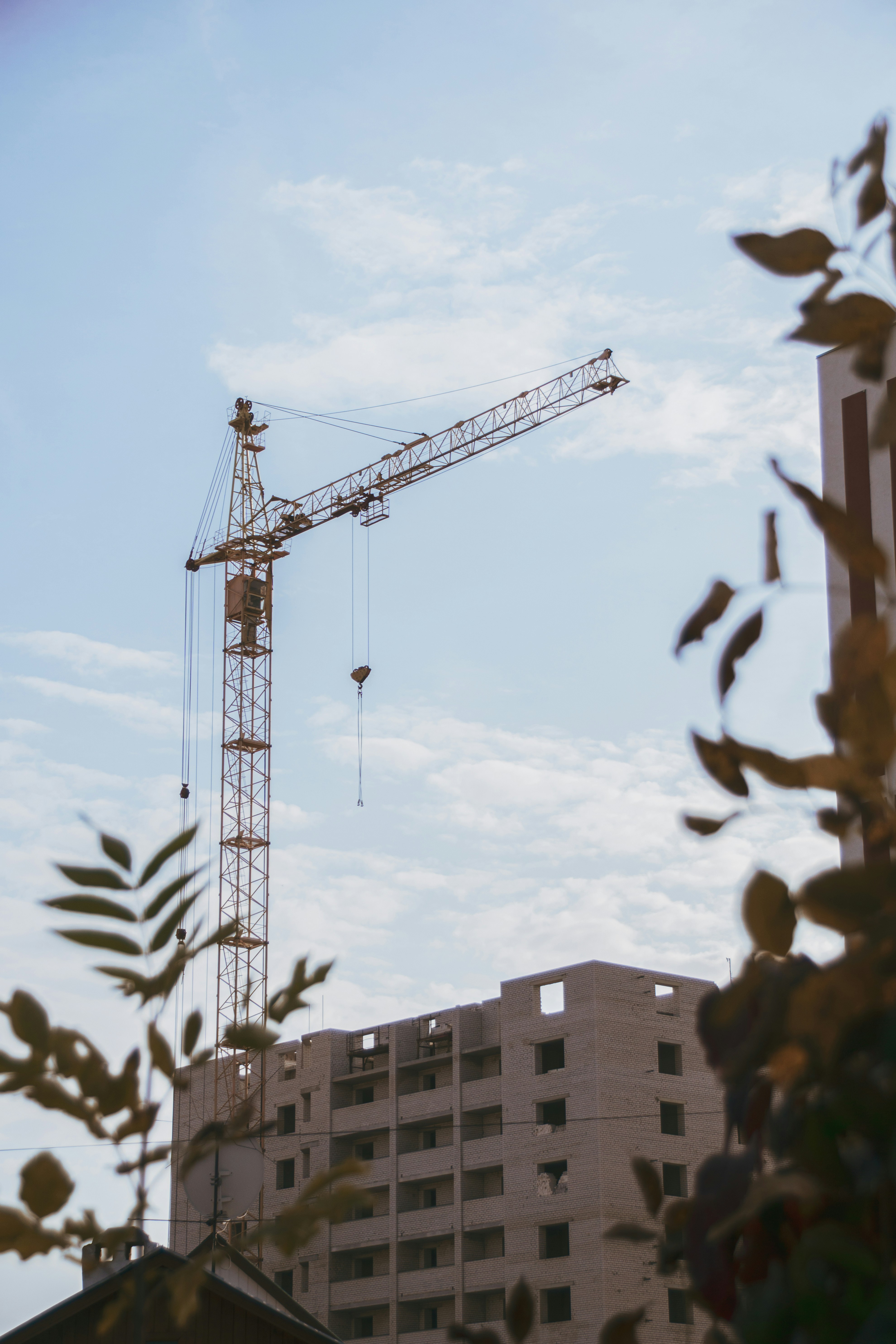 Construction crane near unfinished building under sky
