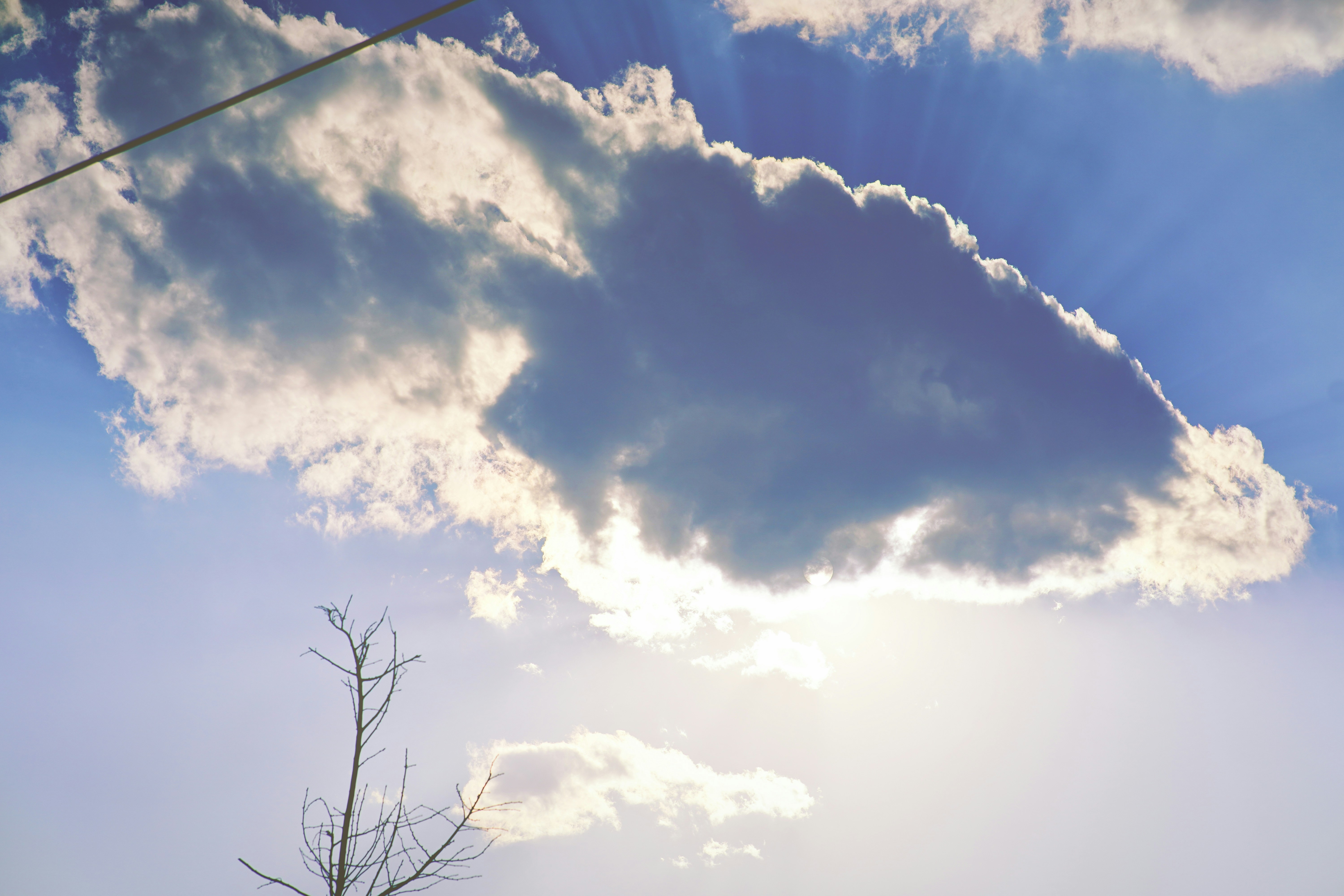 Sun shines through dramatic clouds in a blue sky.