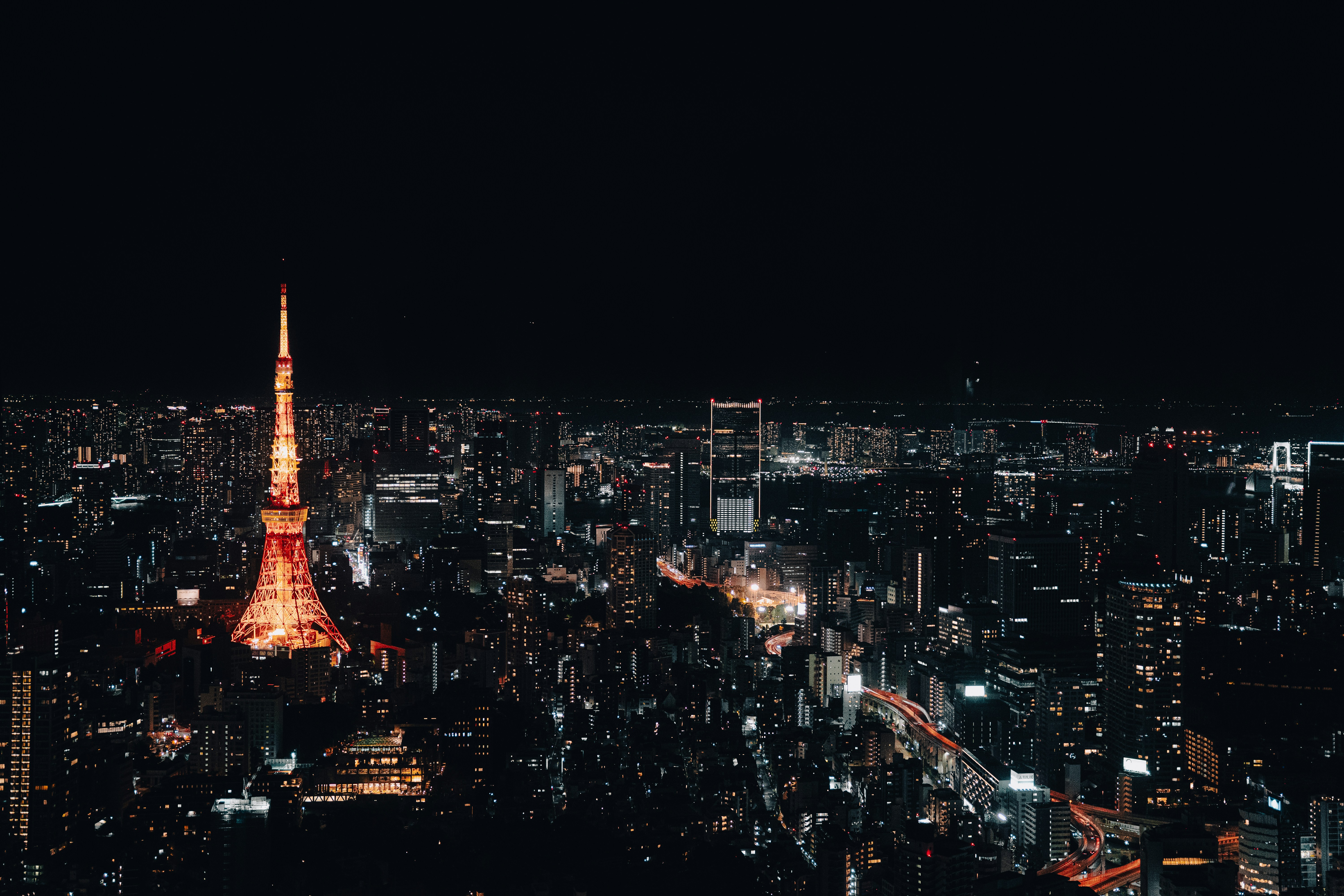 Tokyo Tower glows in vibrant orange against a sprawling cityscape at night, showcasing the dynamic energy of urban life.