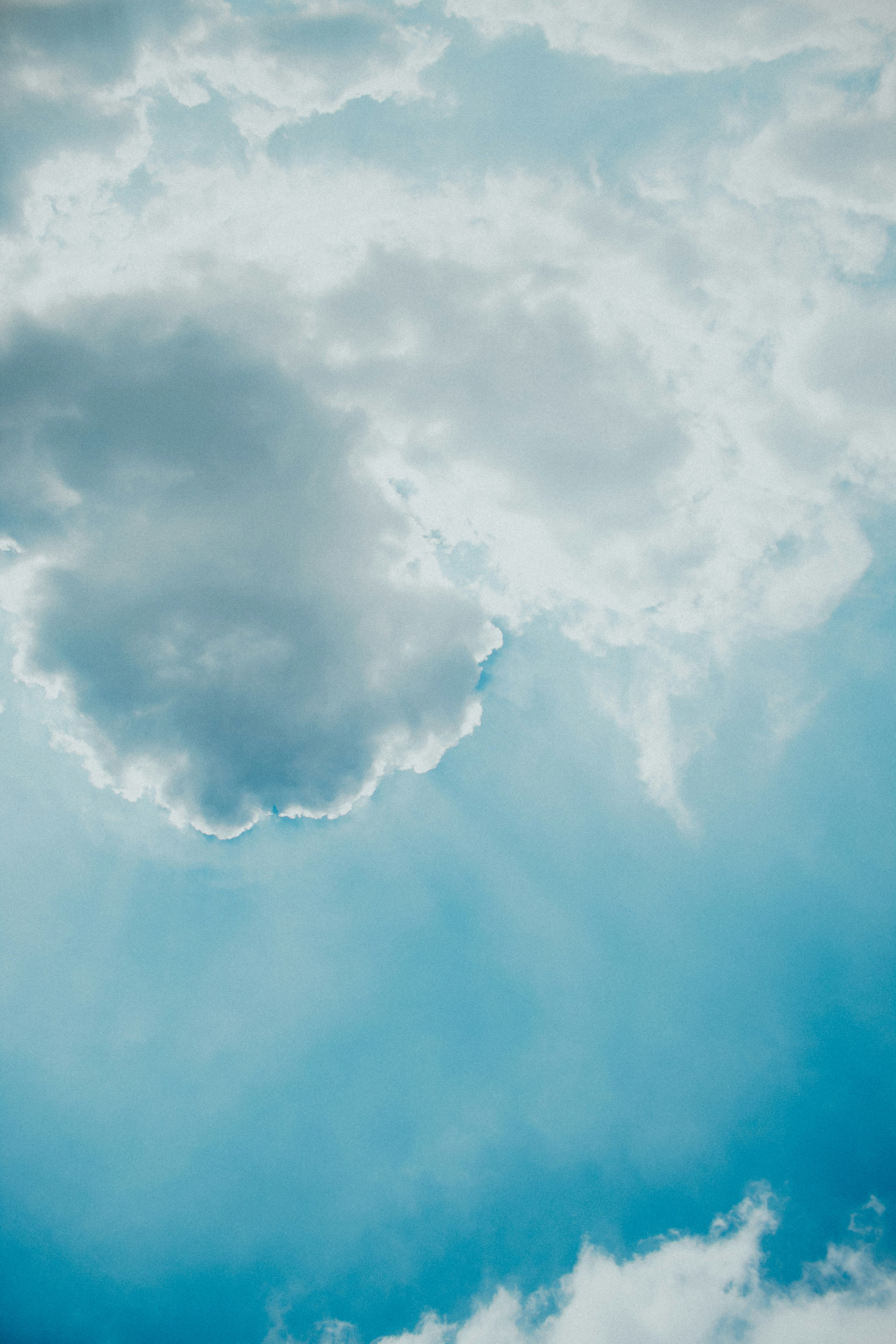White clouds on a partly cloudy blue sky in a daylight | A cloudy sky with sunbeams shining through