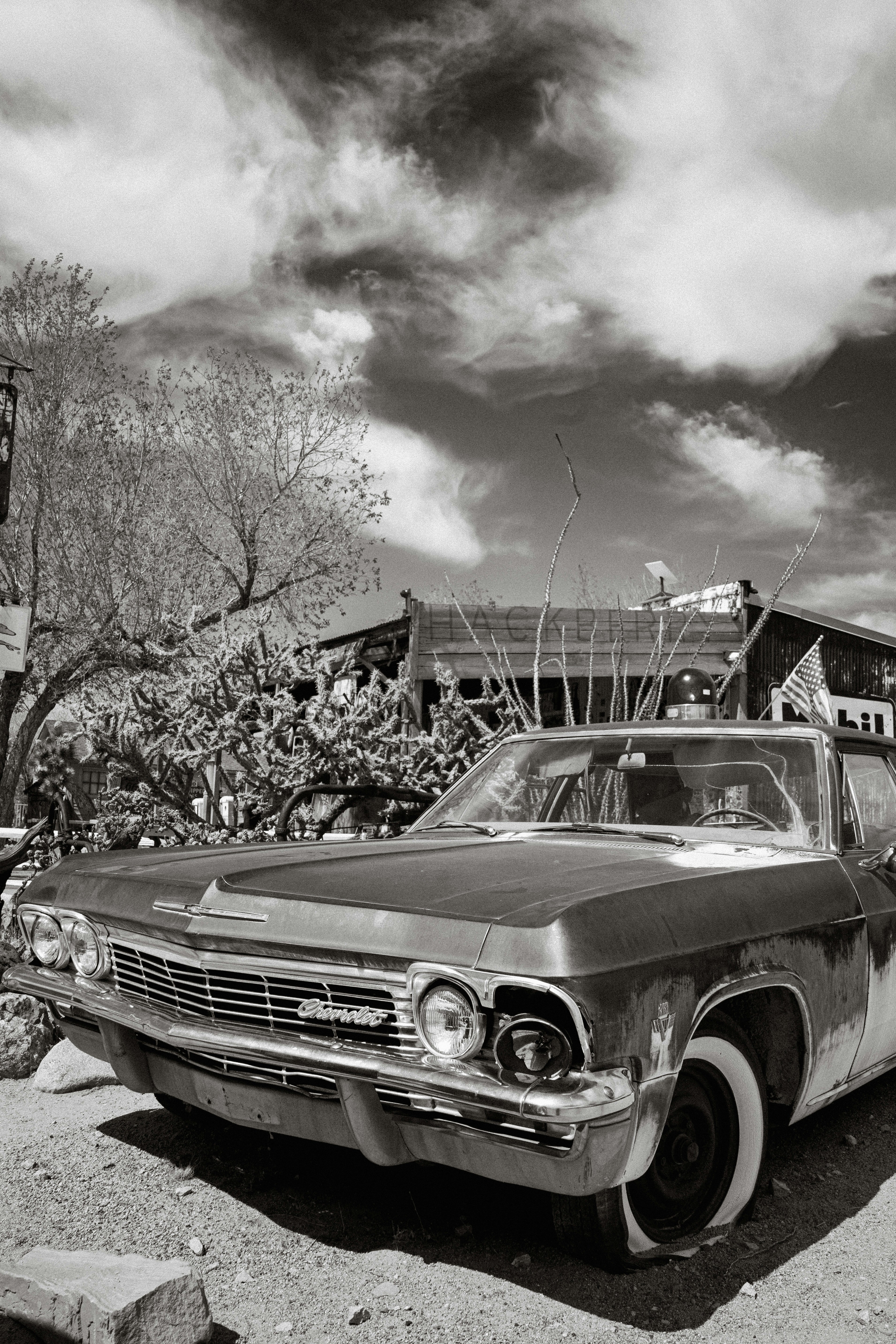 Front-Quarter Chrome Relic in a Desert Junkyard Beneath a Looming Sky