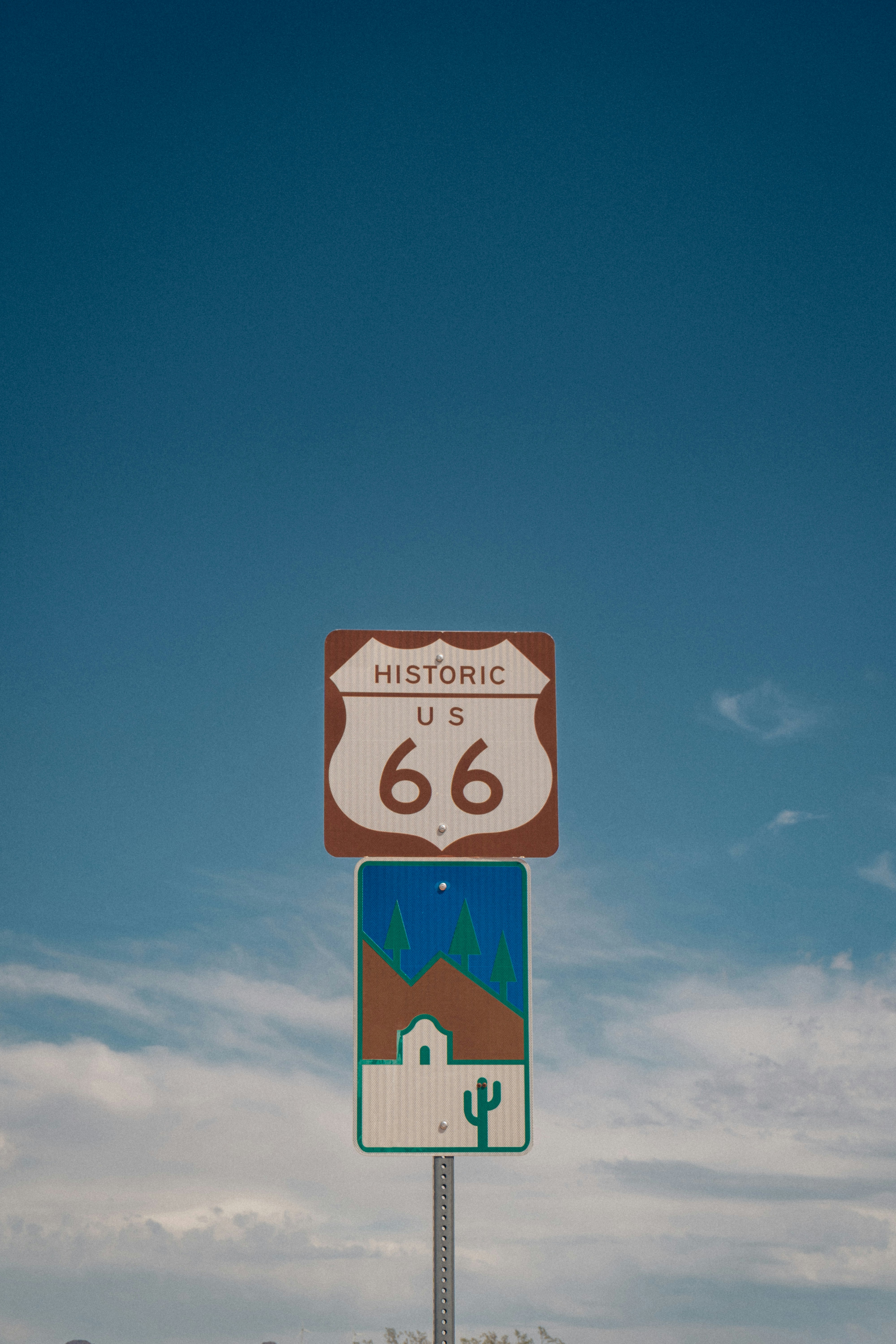 Historic Route 66 sign under blue sky | Historic us 66 sign with desert landscape