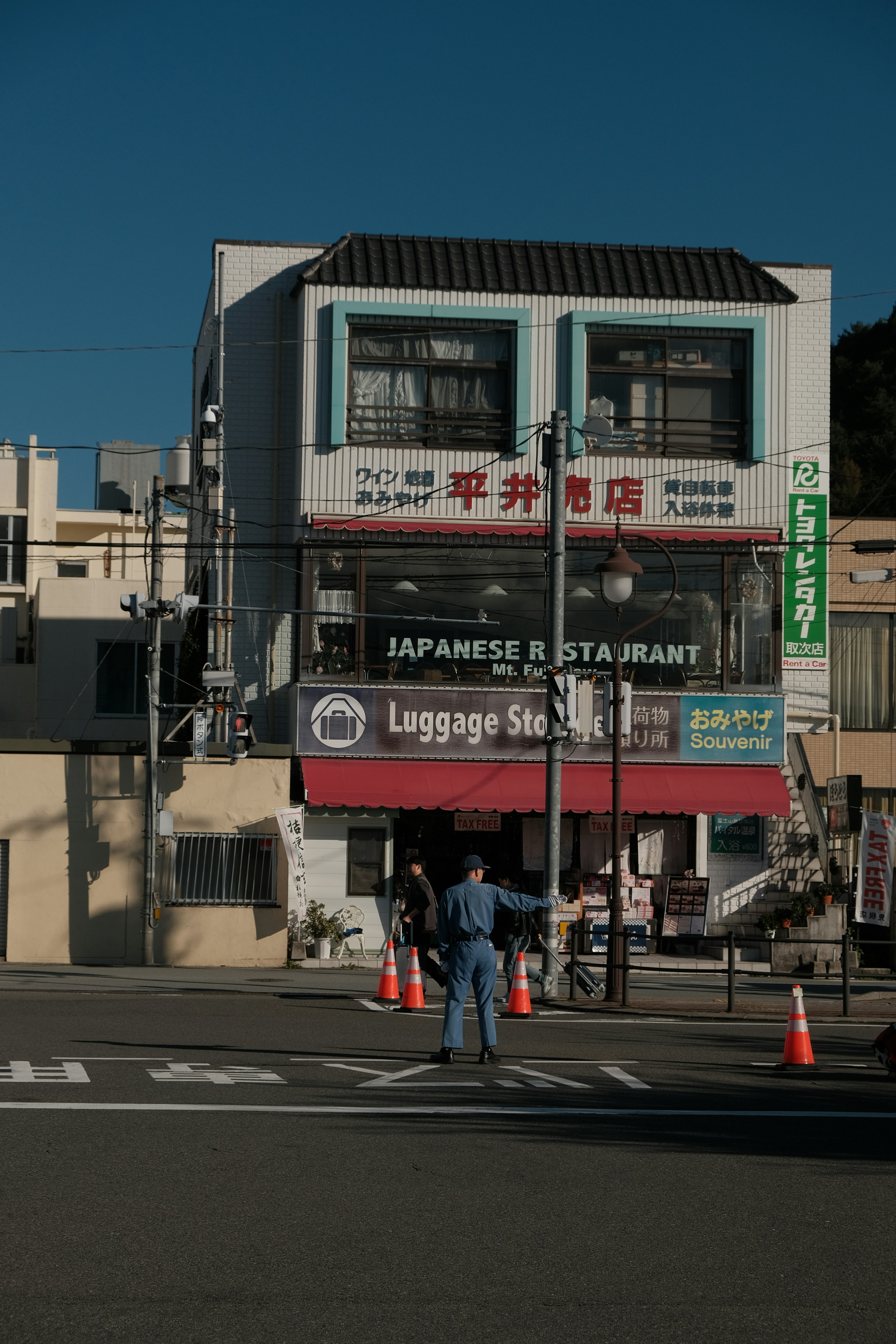 Blue-Uniform Crossroads: A Luggage Store Front Beneath Japanese Signage