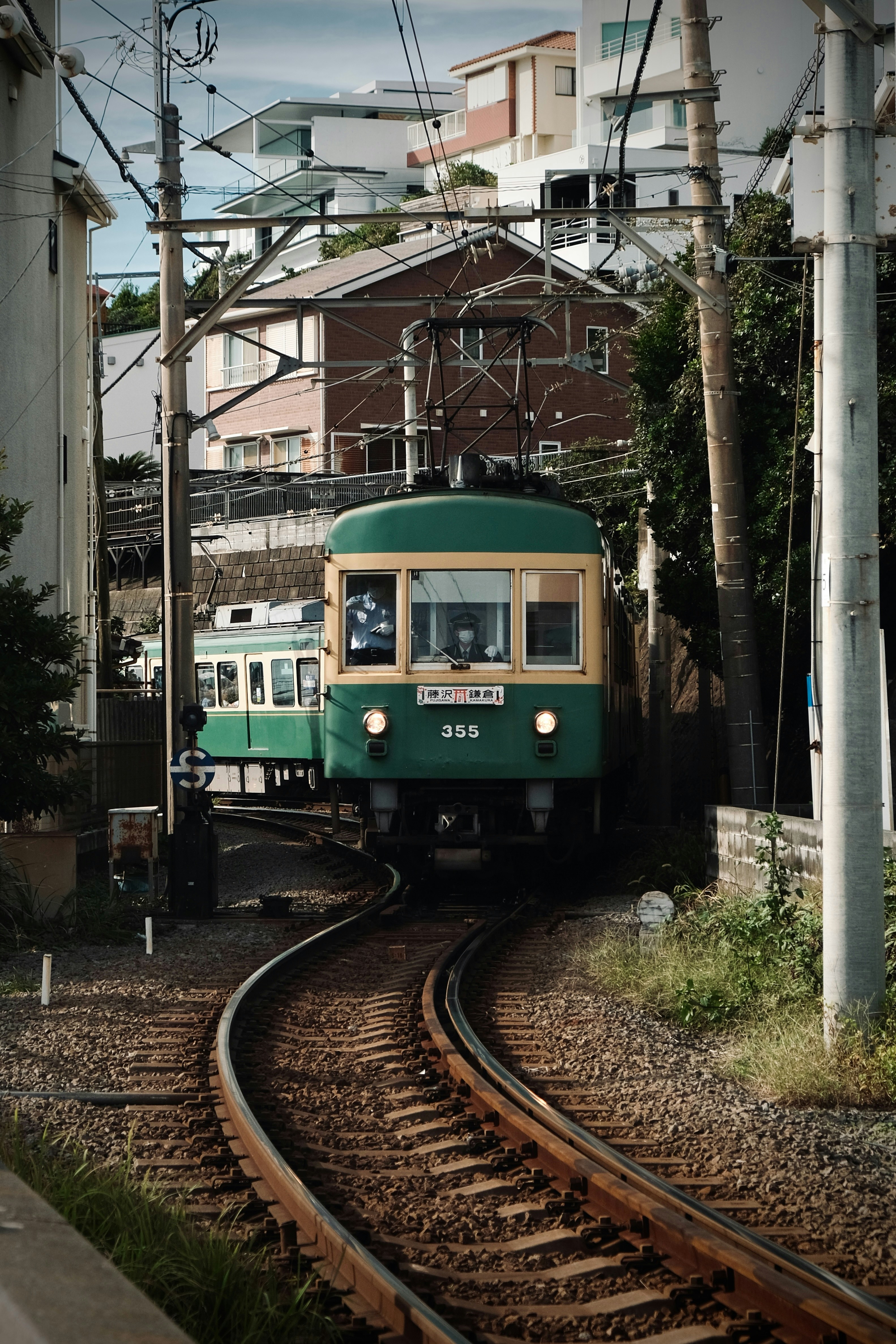 Green train on tracks in a residential area.