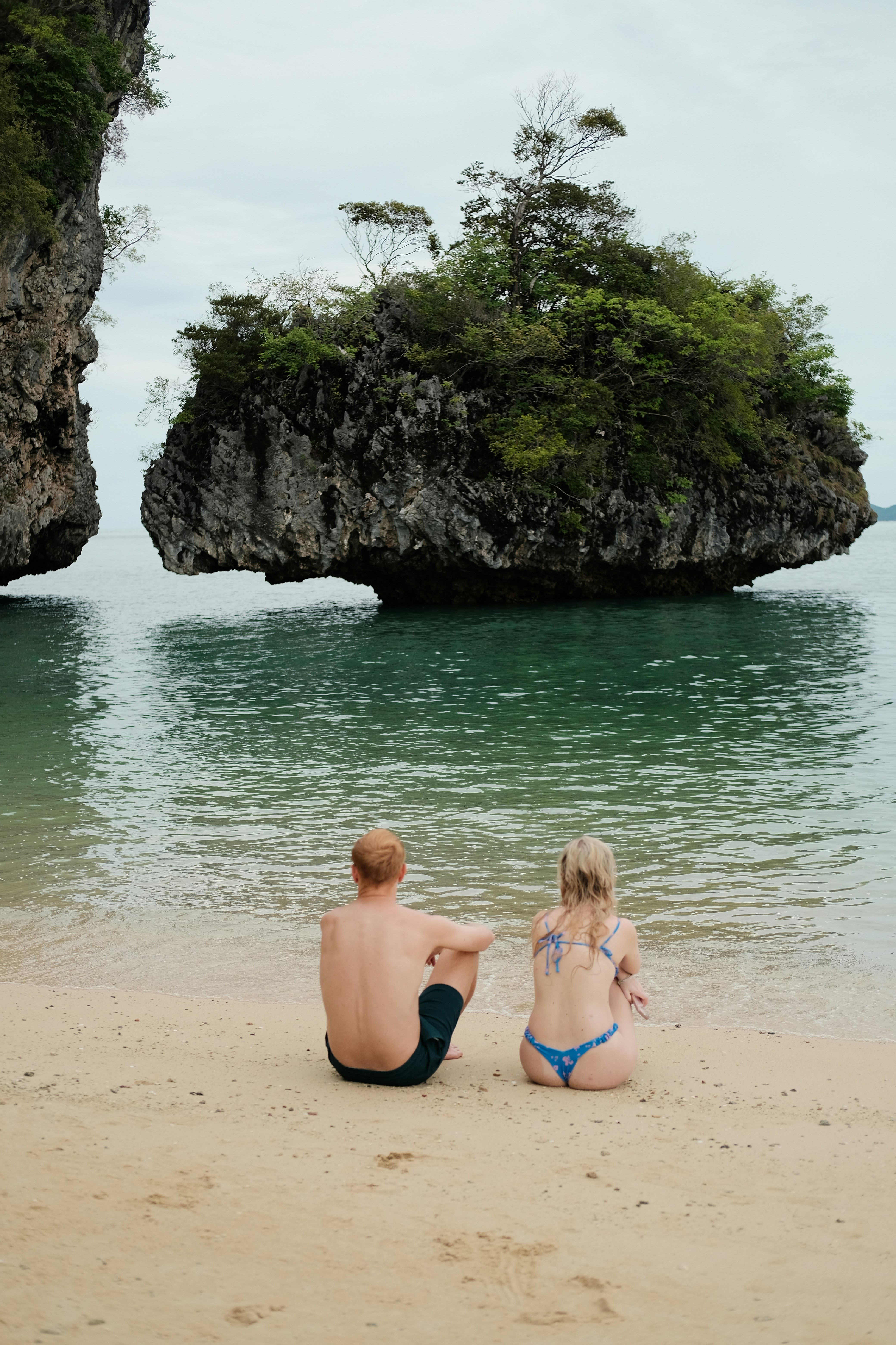 Couple sitting on beach looking at island