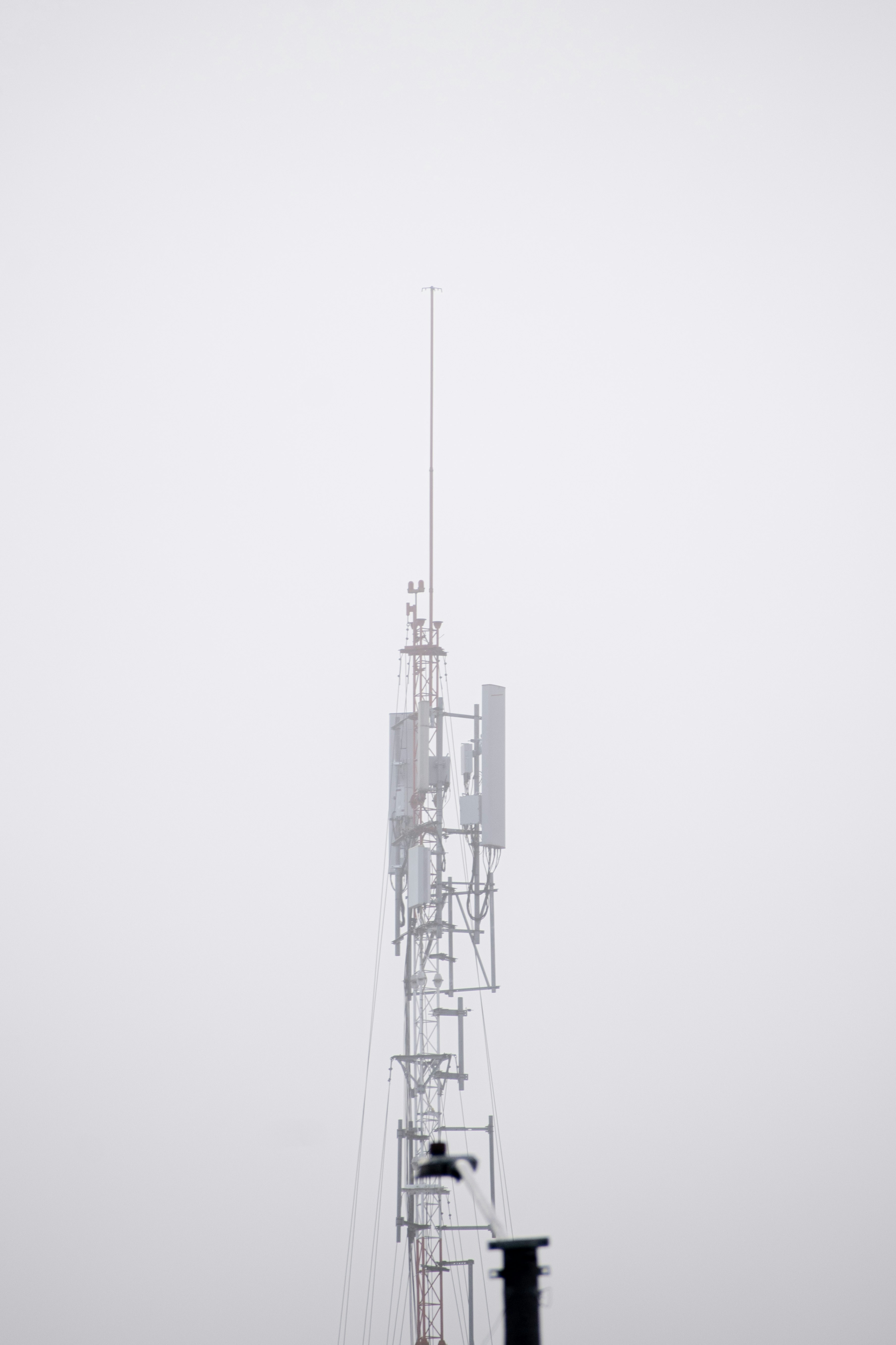 A tall cell tower stands against a foggy sky.
