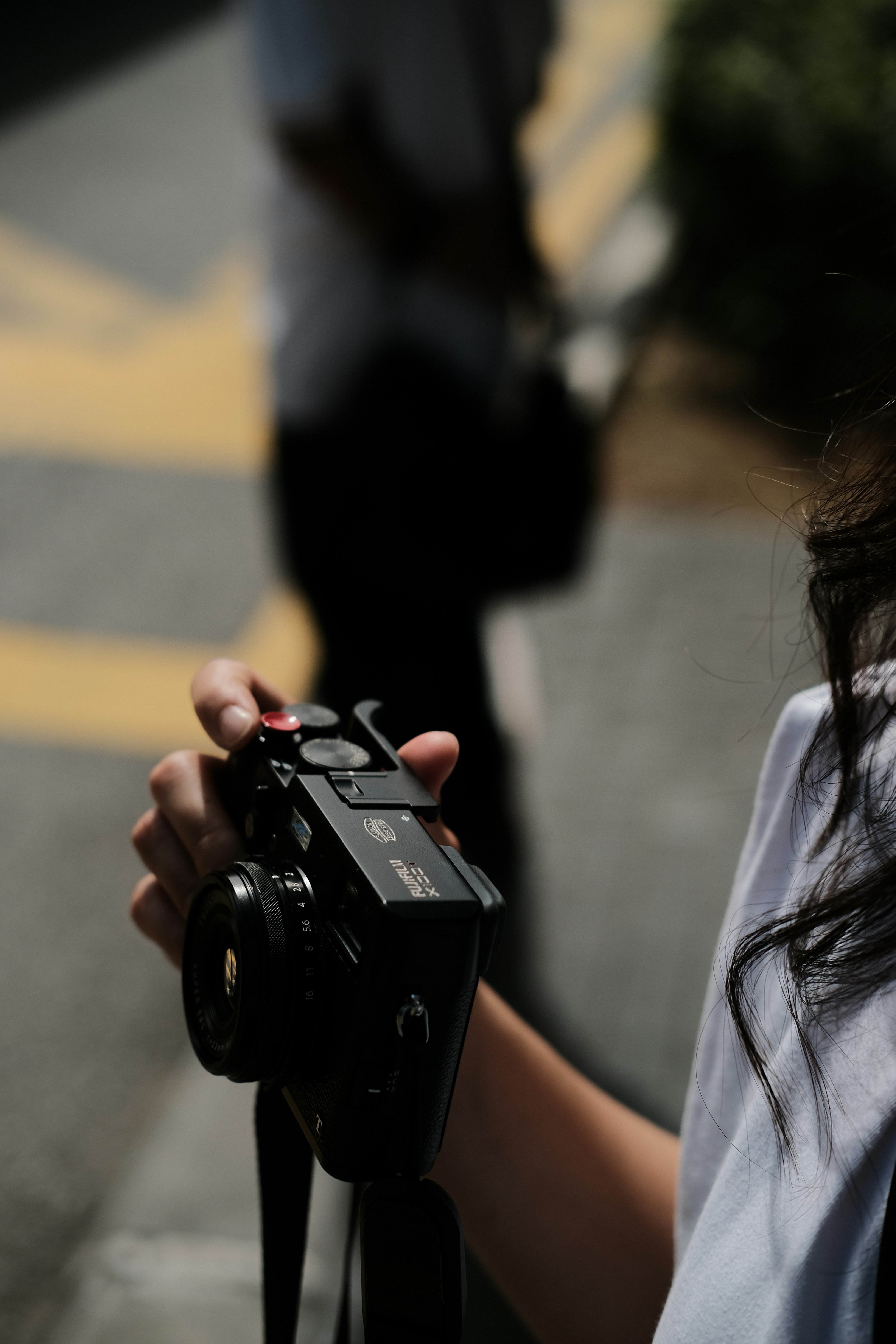 A person holding a Fujifilm X-E4 camera, poised to capture the world around them. The scene reflects a vibrant urban environment.