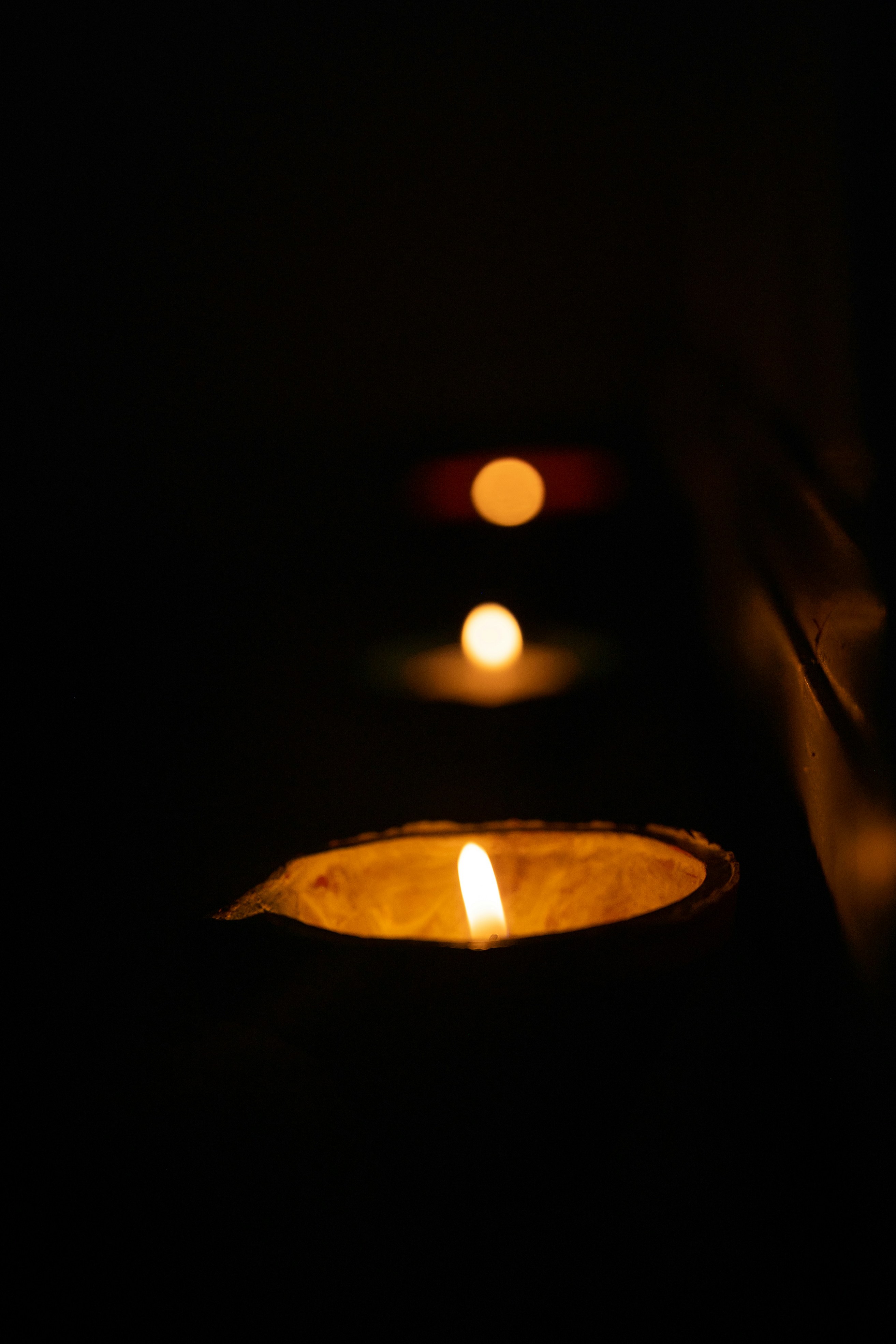 A lit candle in a dark room with bokeh lights