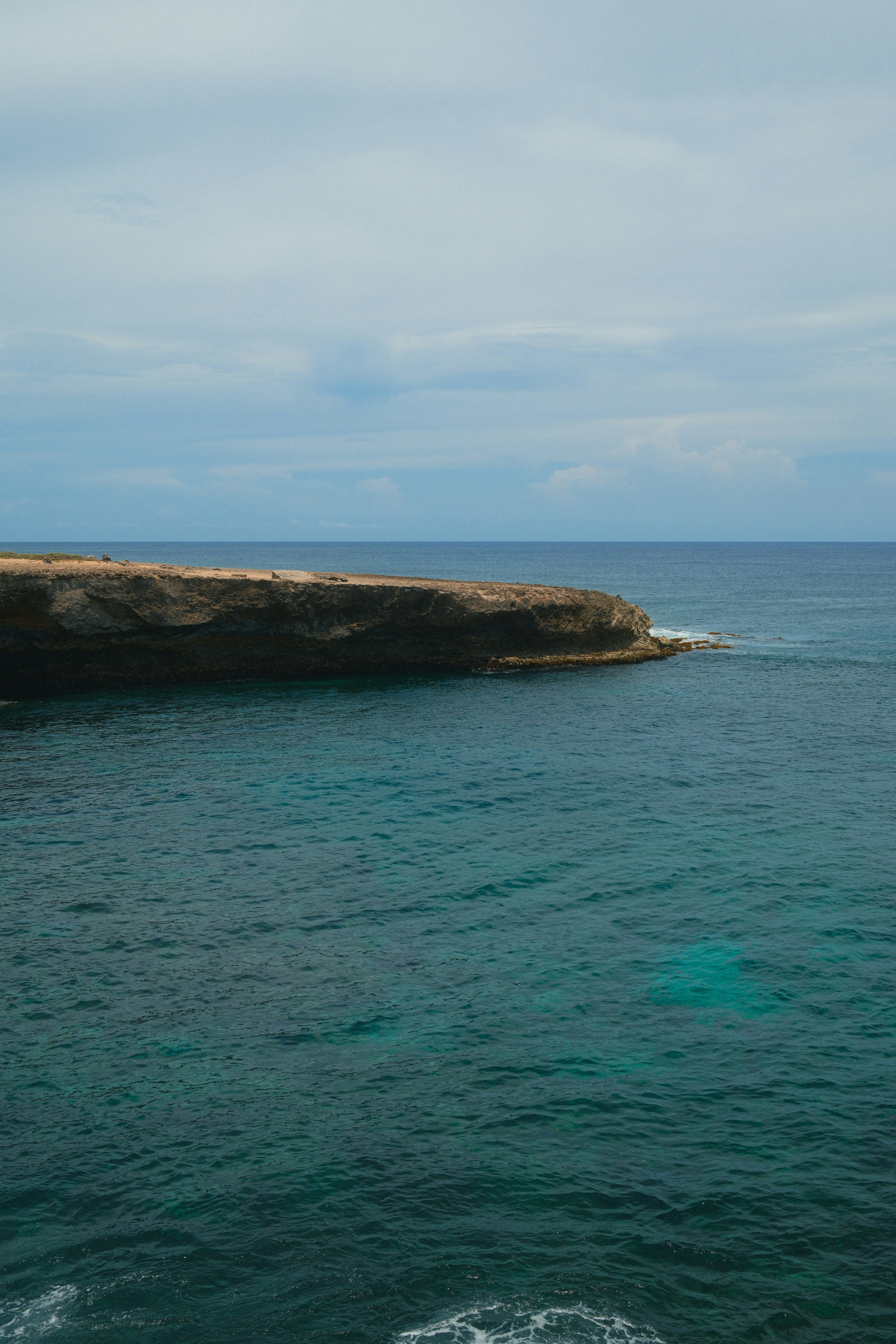 La costa rocosa se encuentra con el océano turquesa bajo un cielo ...