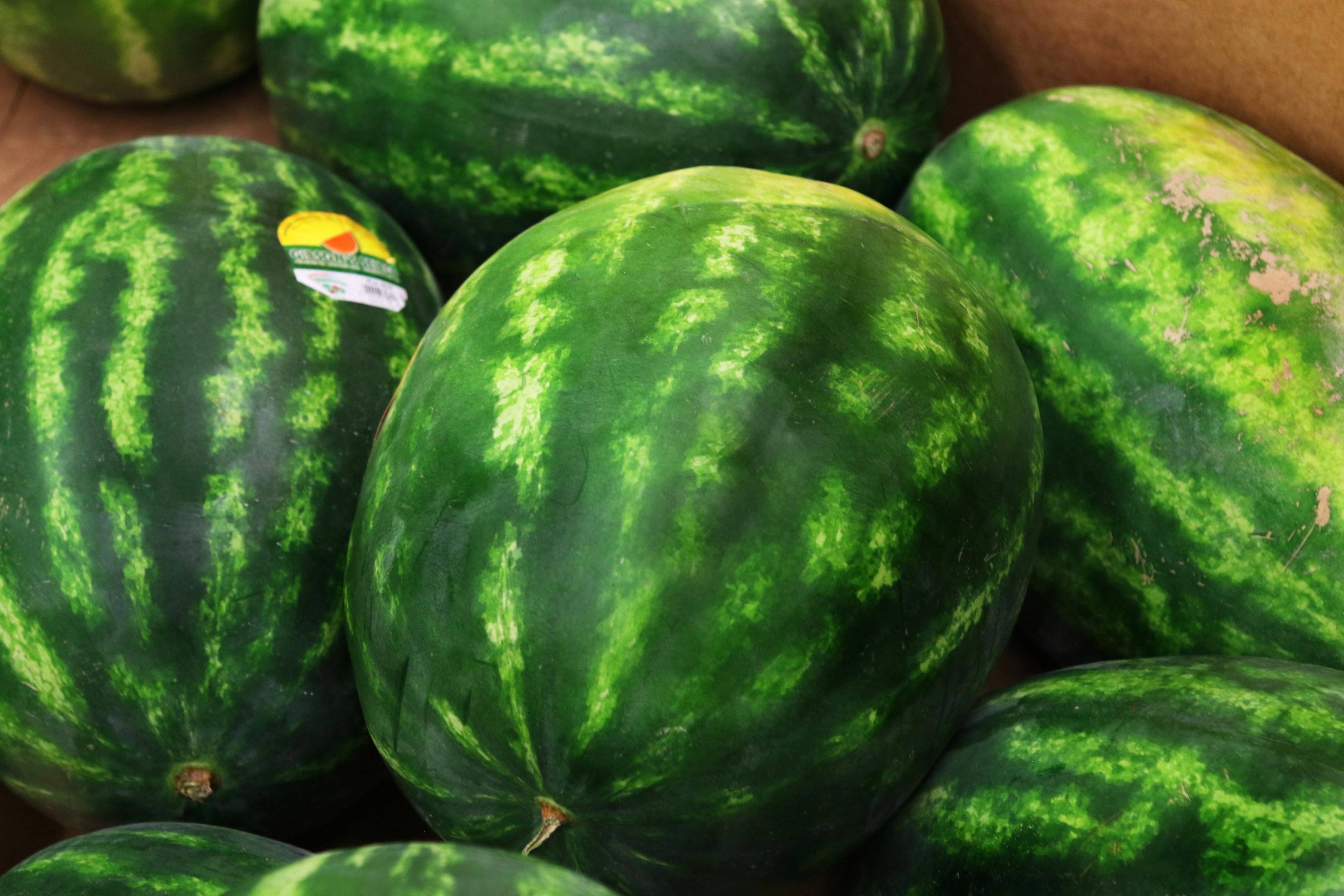 Several ripe watermelons with dark green stripes.
