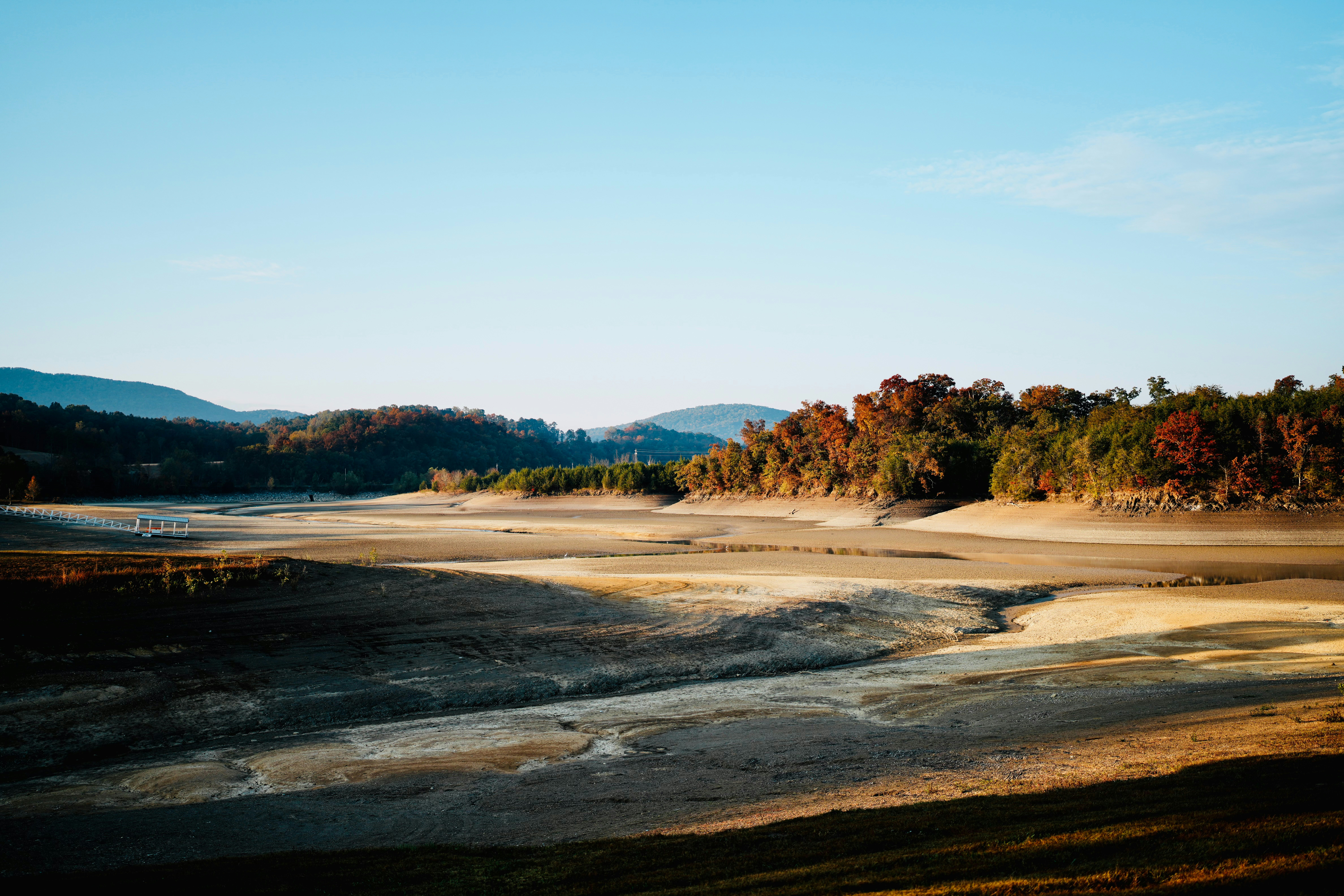 Dry lake bed with trees and hills under sky