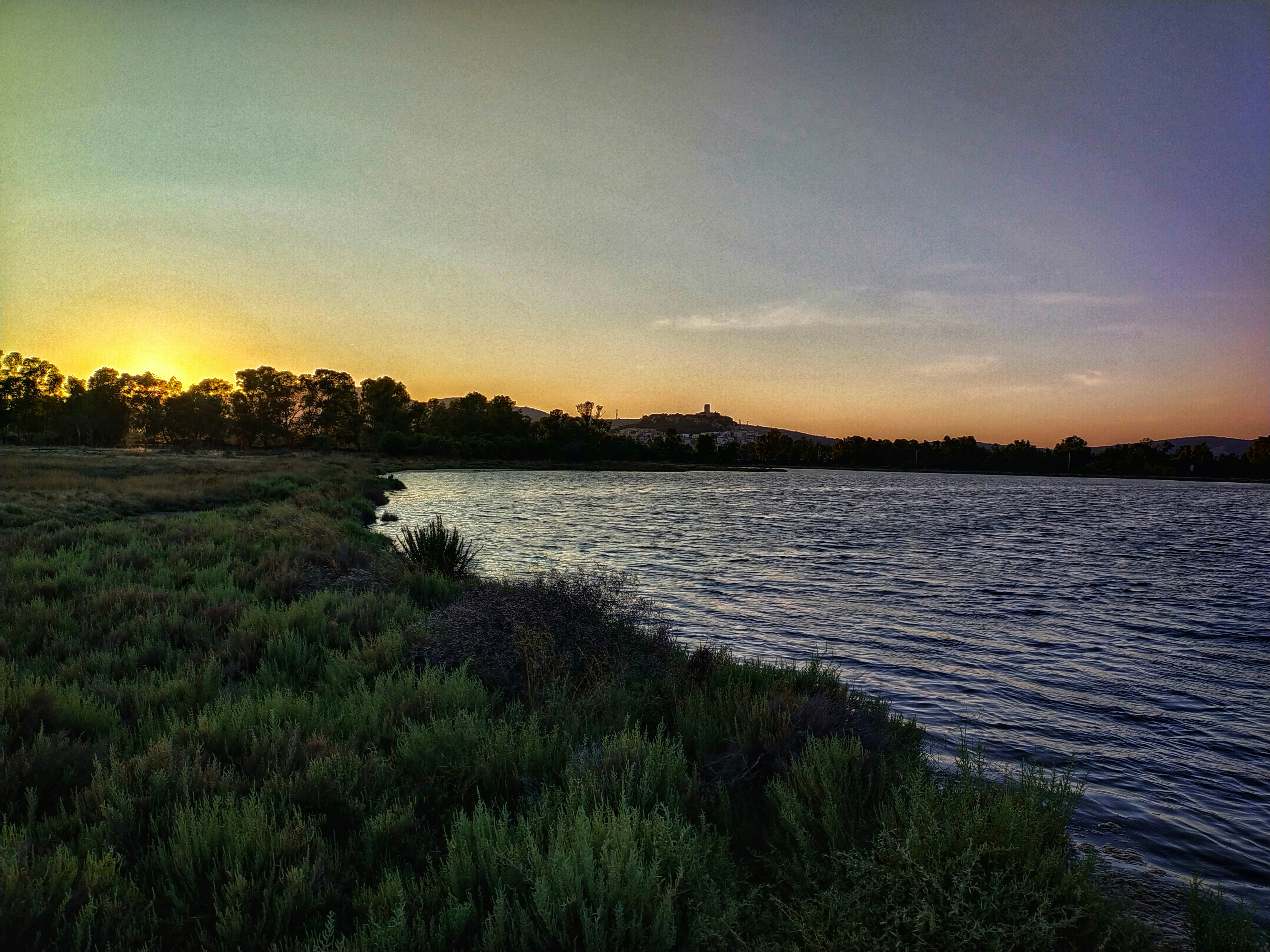 Sunset over a calm lake with grassy shore