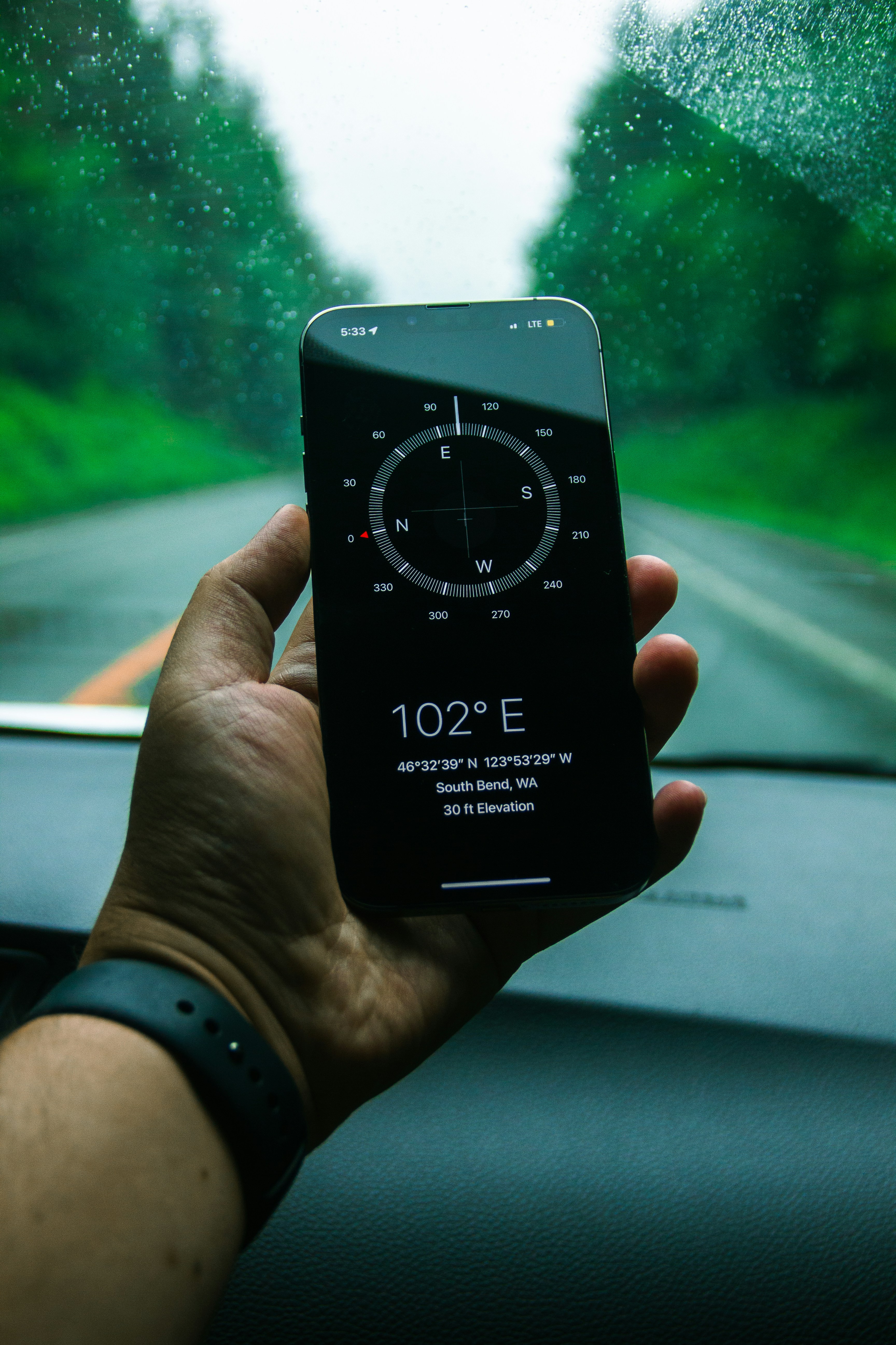 Hand holding smartphone displaying compass and coordinates