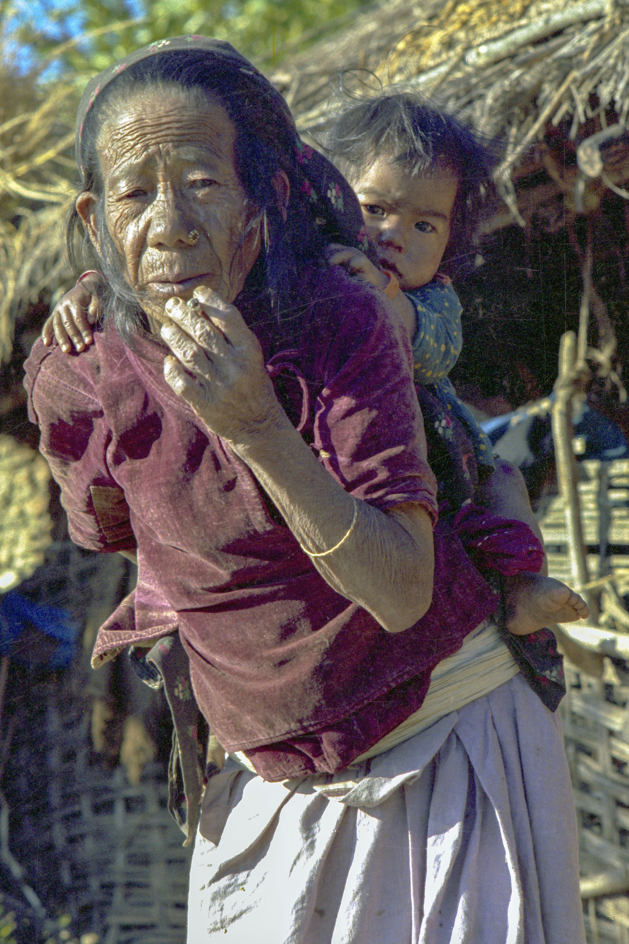 Elderly woman carrying a child on her back, showcasing a deep bond in a rural setting. The warmth of their connection is palpable.