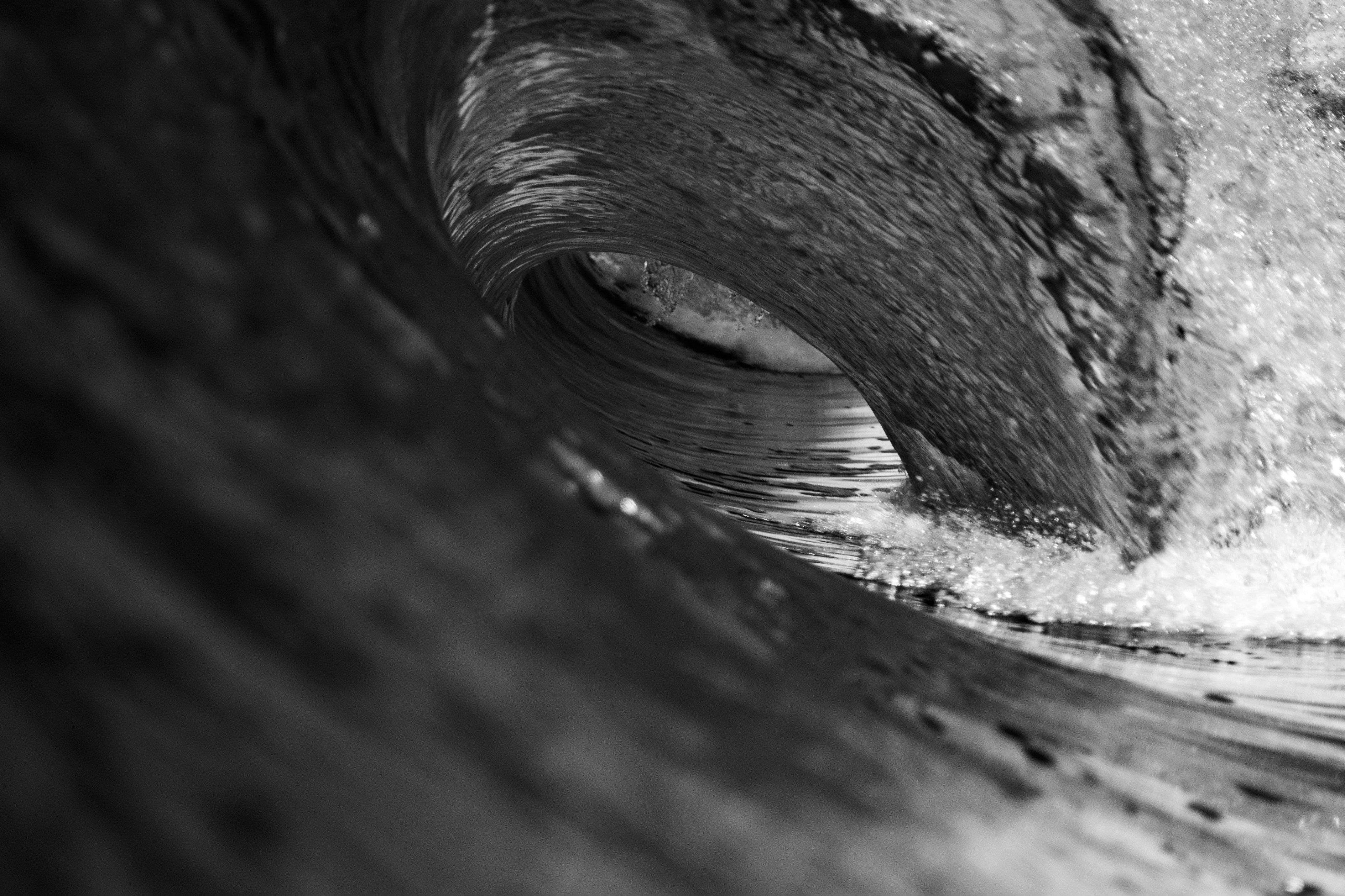 Dynamic wave forming a tunnel as it crashes, showcasing the raw energy of the ocean in monochrome tones.