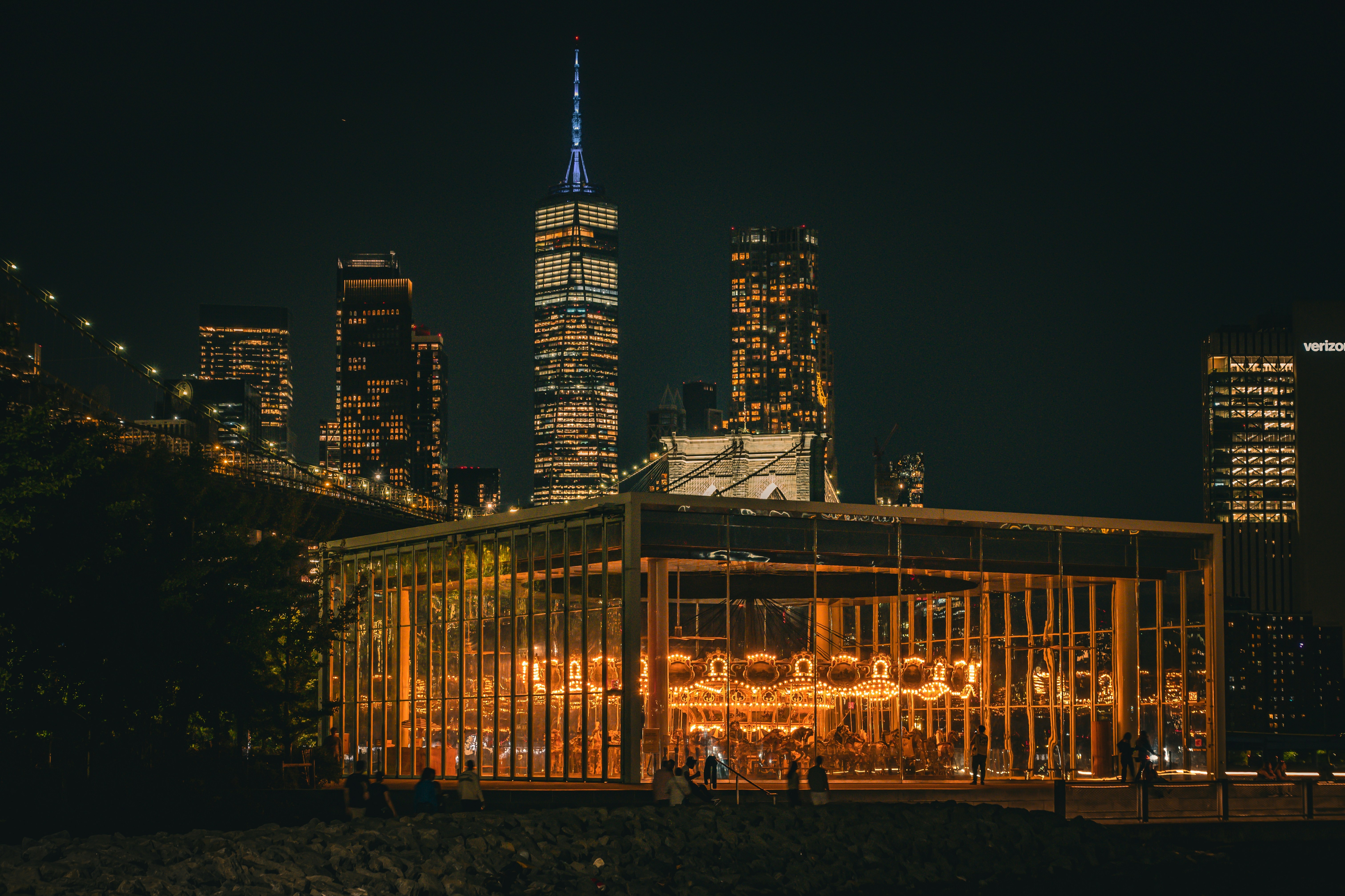 Night view of a brightly lit carousel with city skyline.