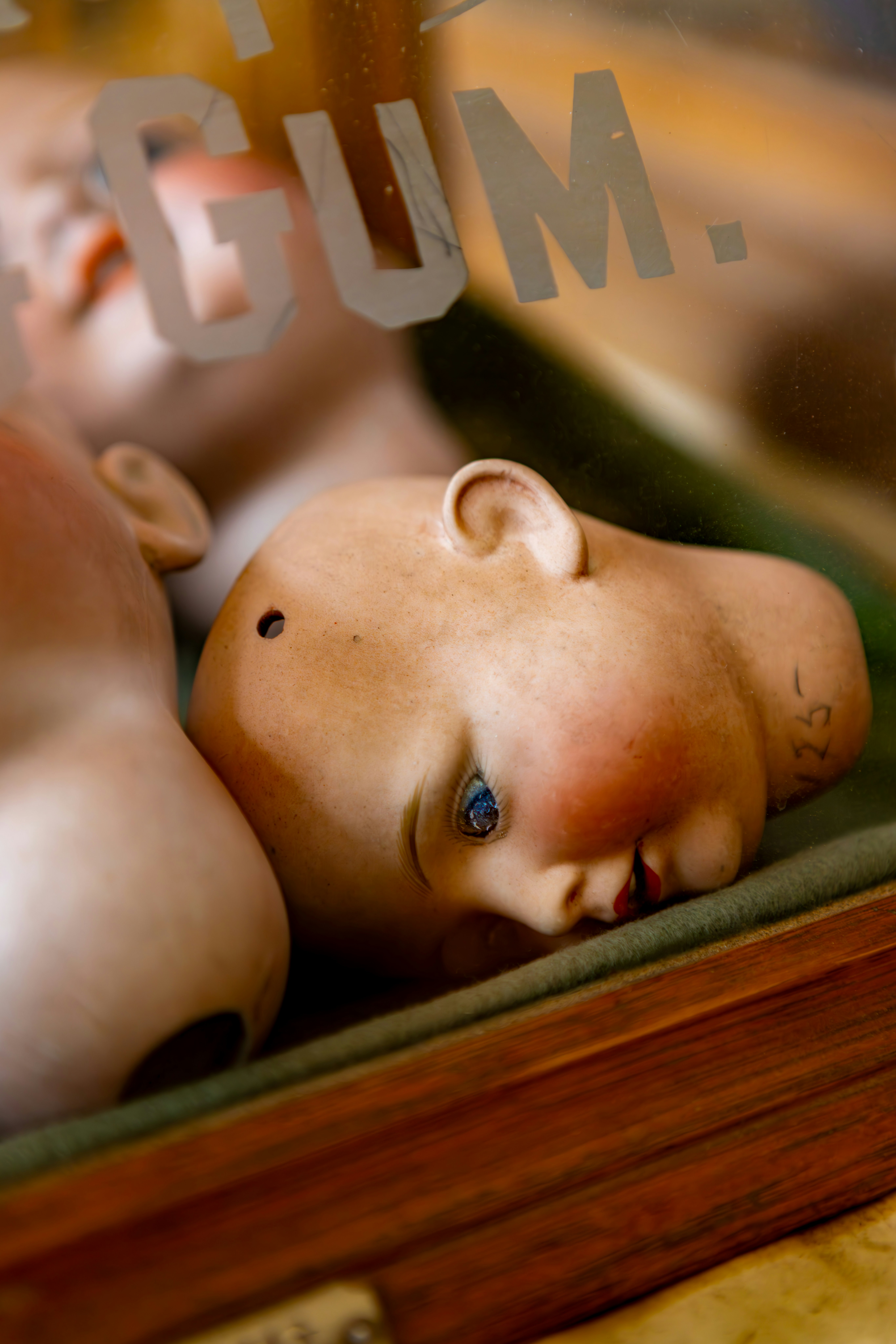 Doll heads from the 1800s still awaiting bodies in a glass chewing gum case in the historic Dry Goods store museum in Virginia City, Montana, USA in August, 2025. | Antique doll heads in a wooden box