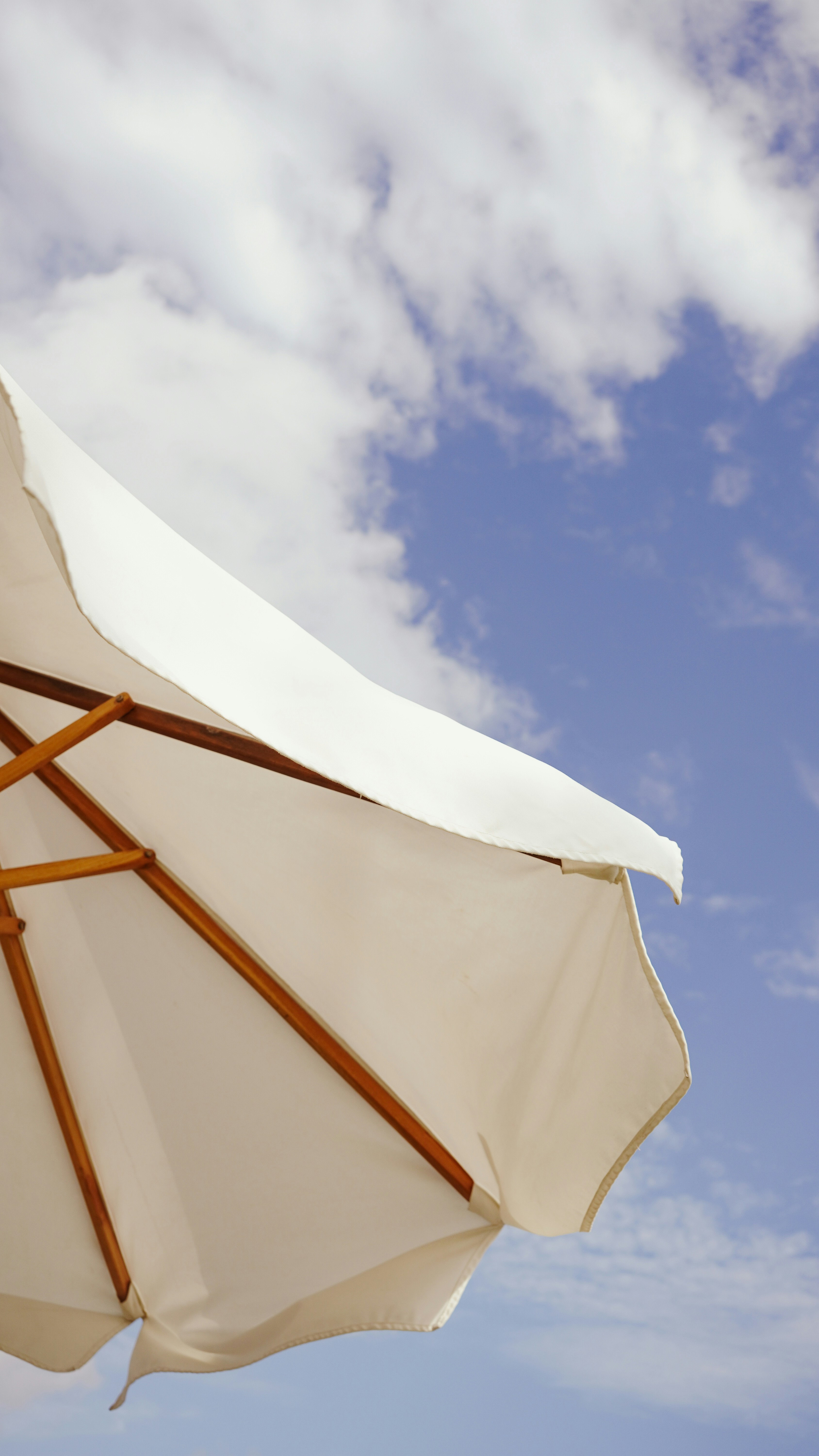 White umbrella against a blue sky with clouds