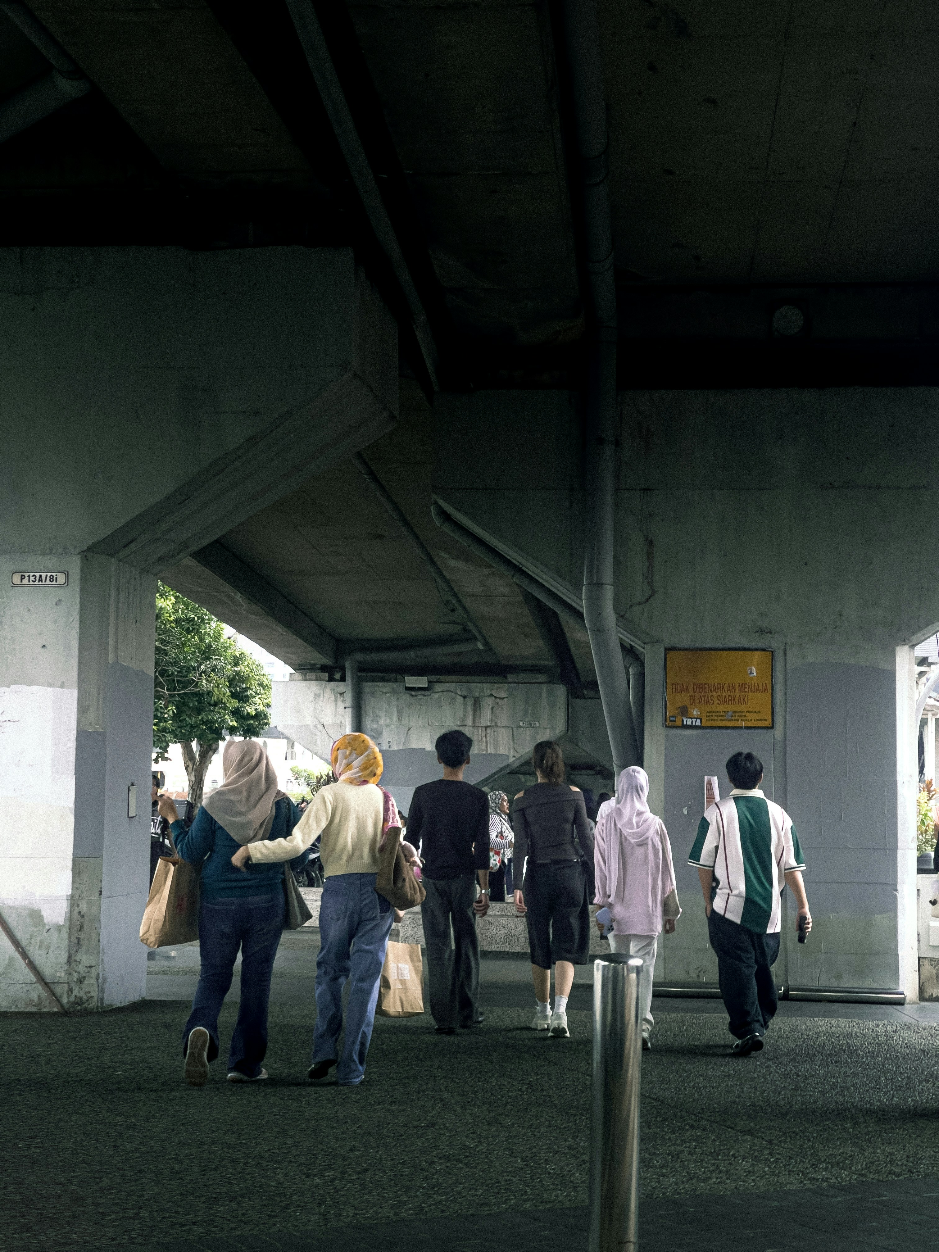 People walking under a concrete overpass