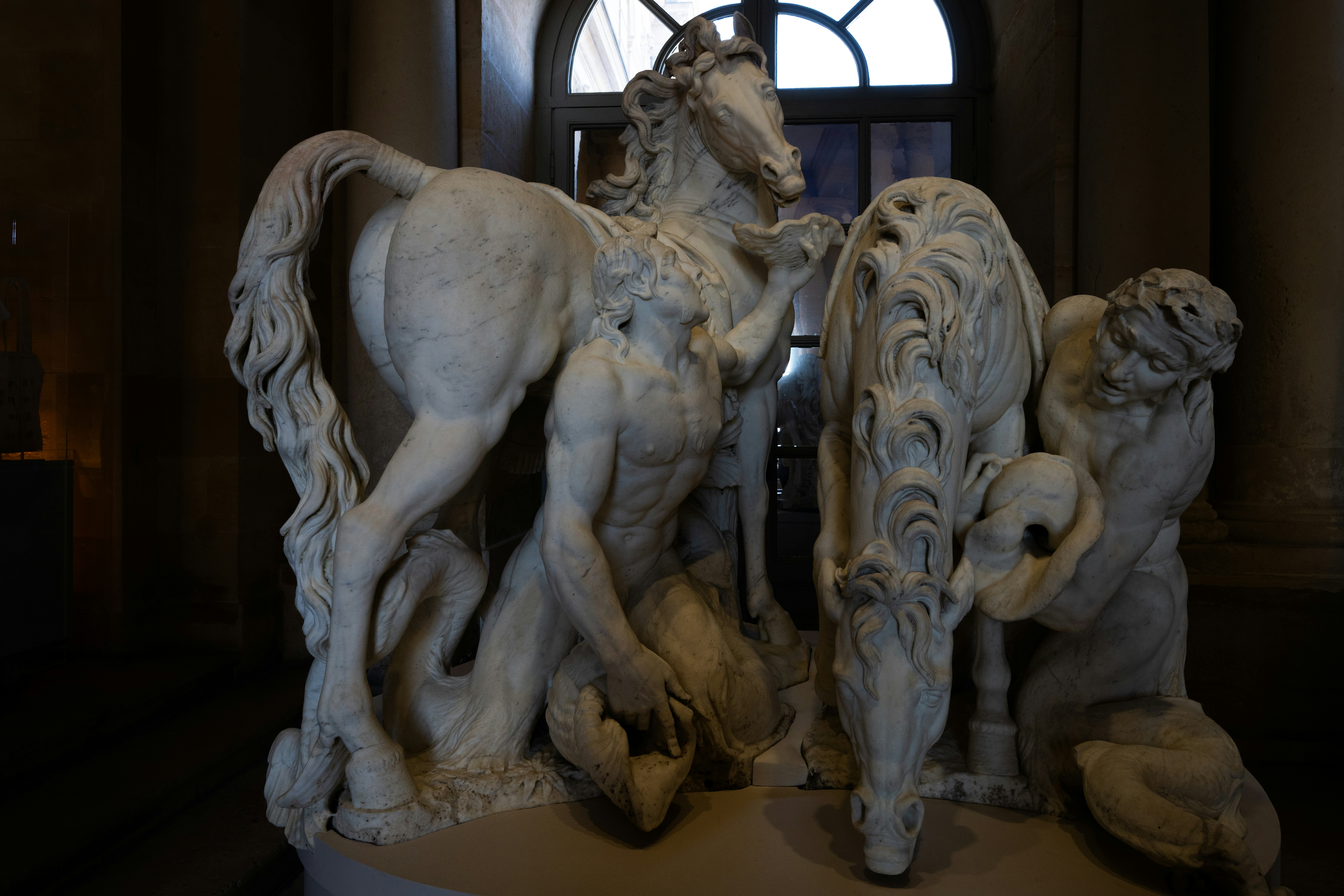 Marble sculpture of men and horses in a museum.