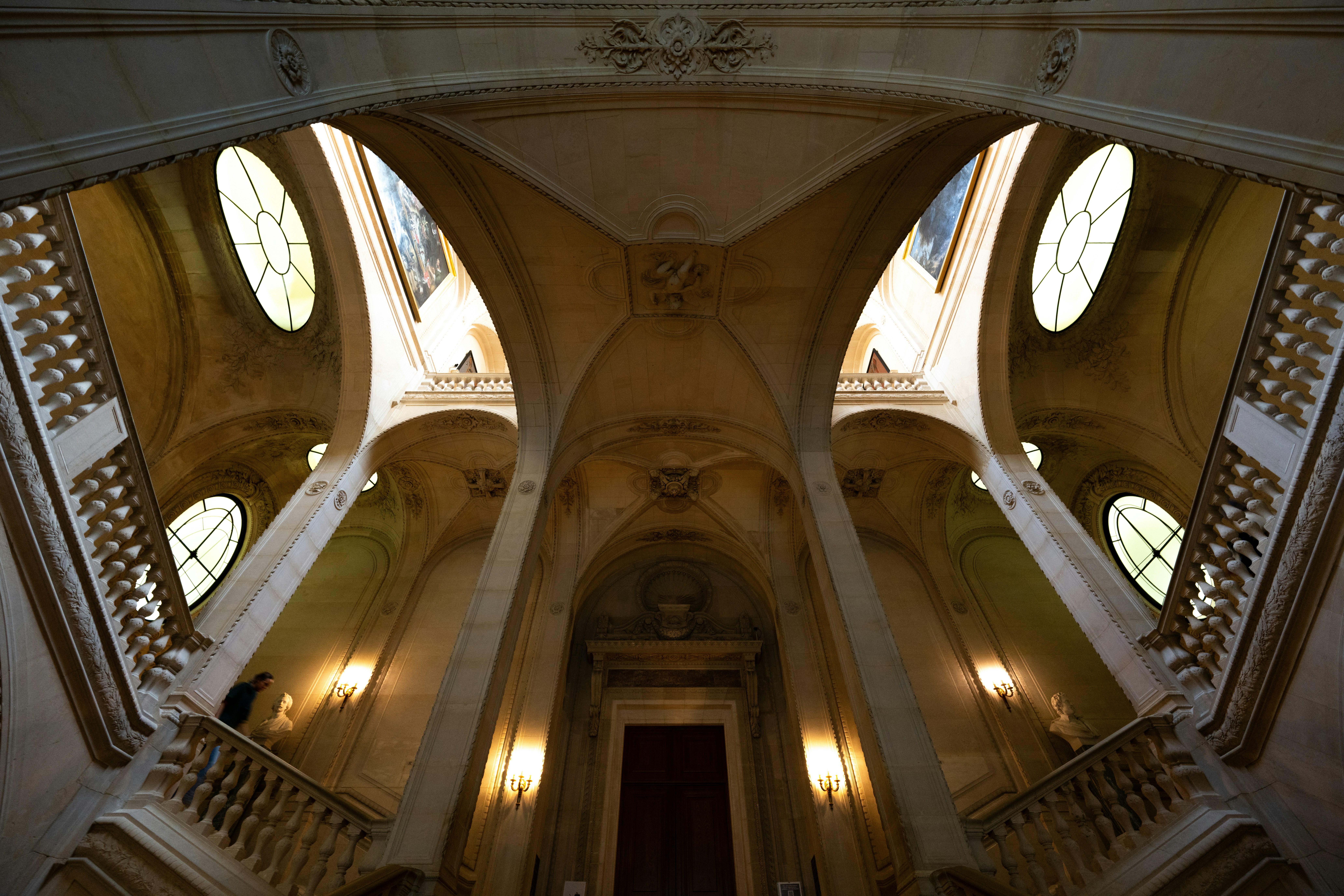 Grand staircase with ornate architecture and oval windows.