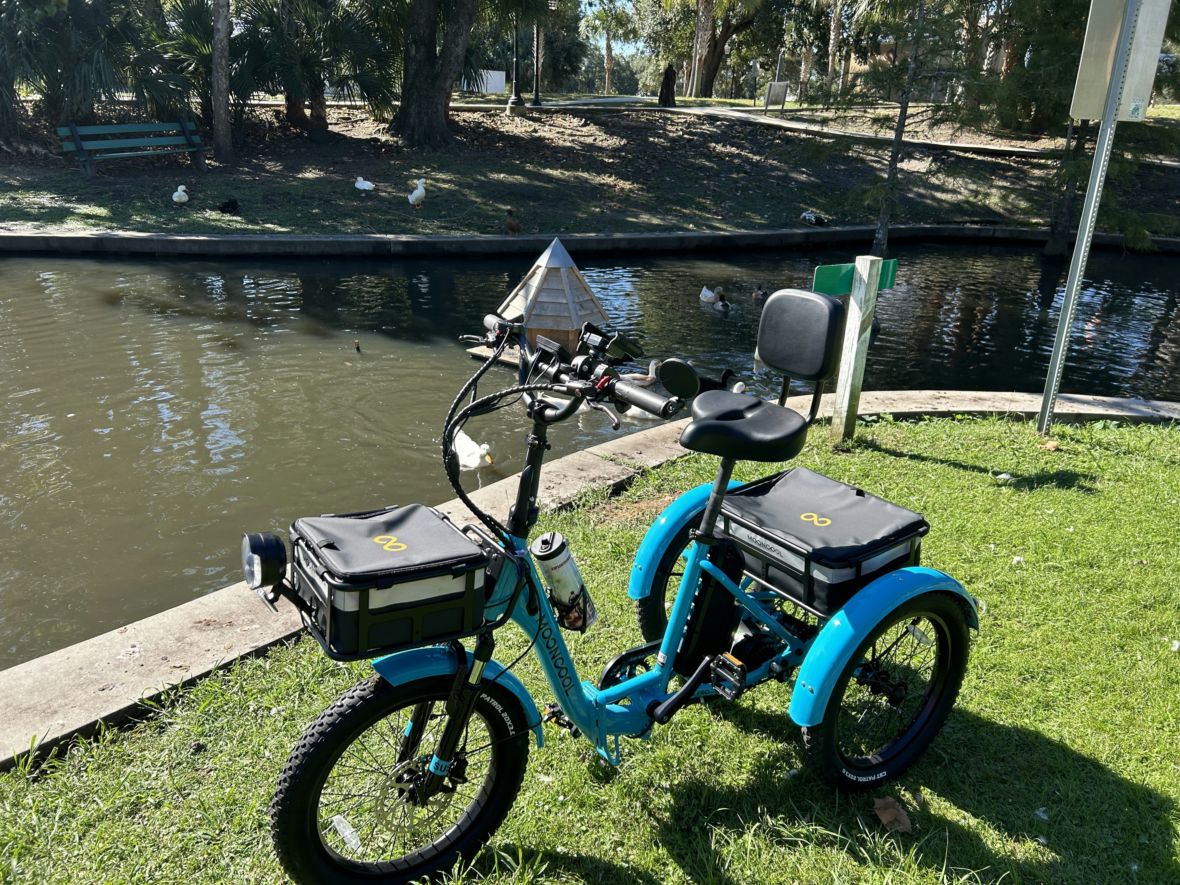 A blue electric tricycle parked by a canal.