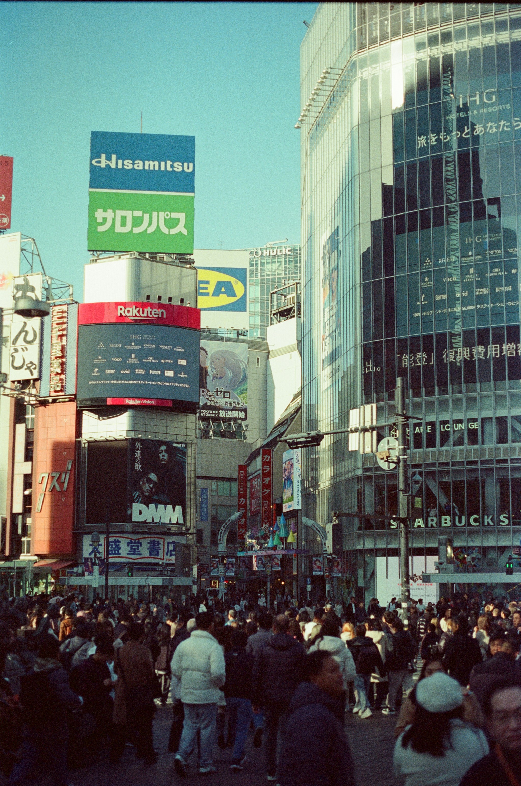 Bustling city square filled with pedestrians amidst towering advertisements and bright billboards. The scene captures the vibrant energy of urban culture.