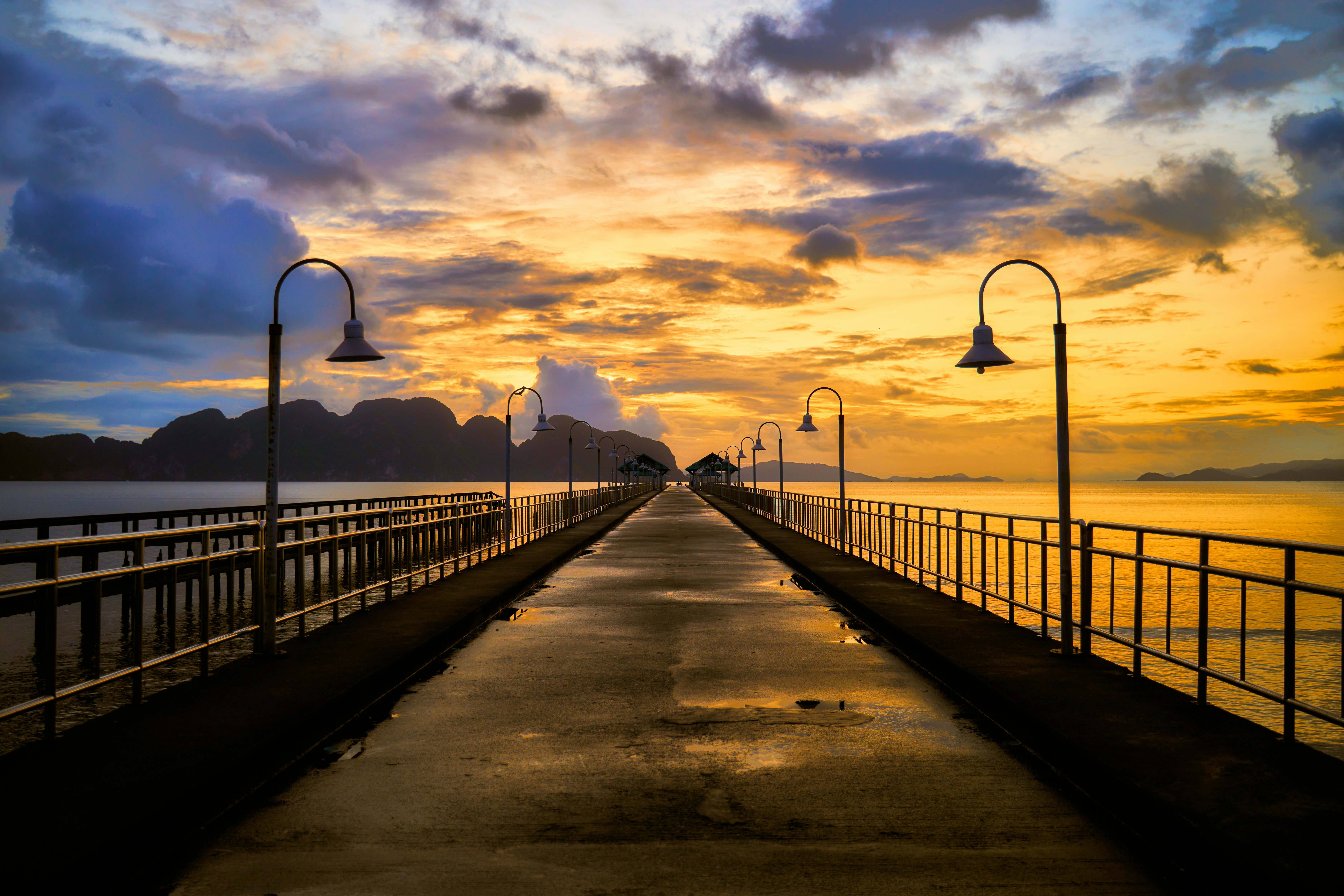 Pier with lamps at sunset over calm ocean
