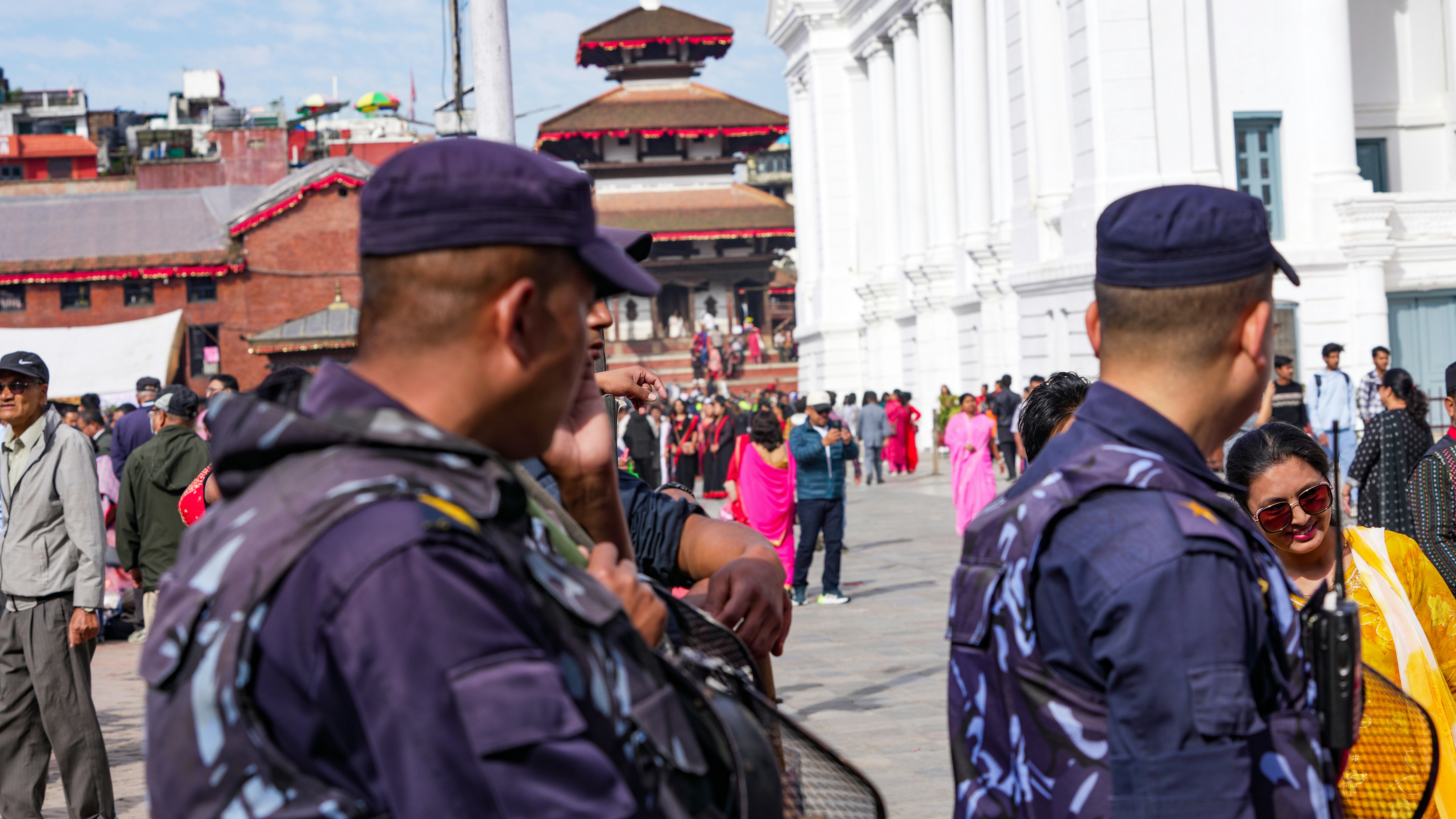 Two security personnel in uniform engage with a vibrant crowd at a historical site, showcasing a blend of tradition and modernity.