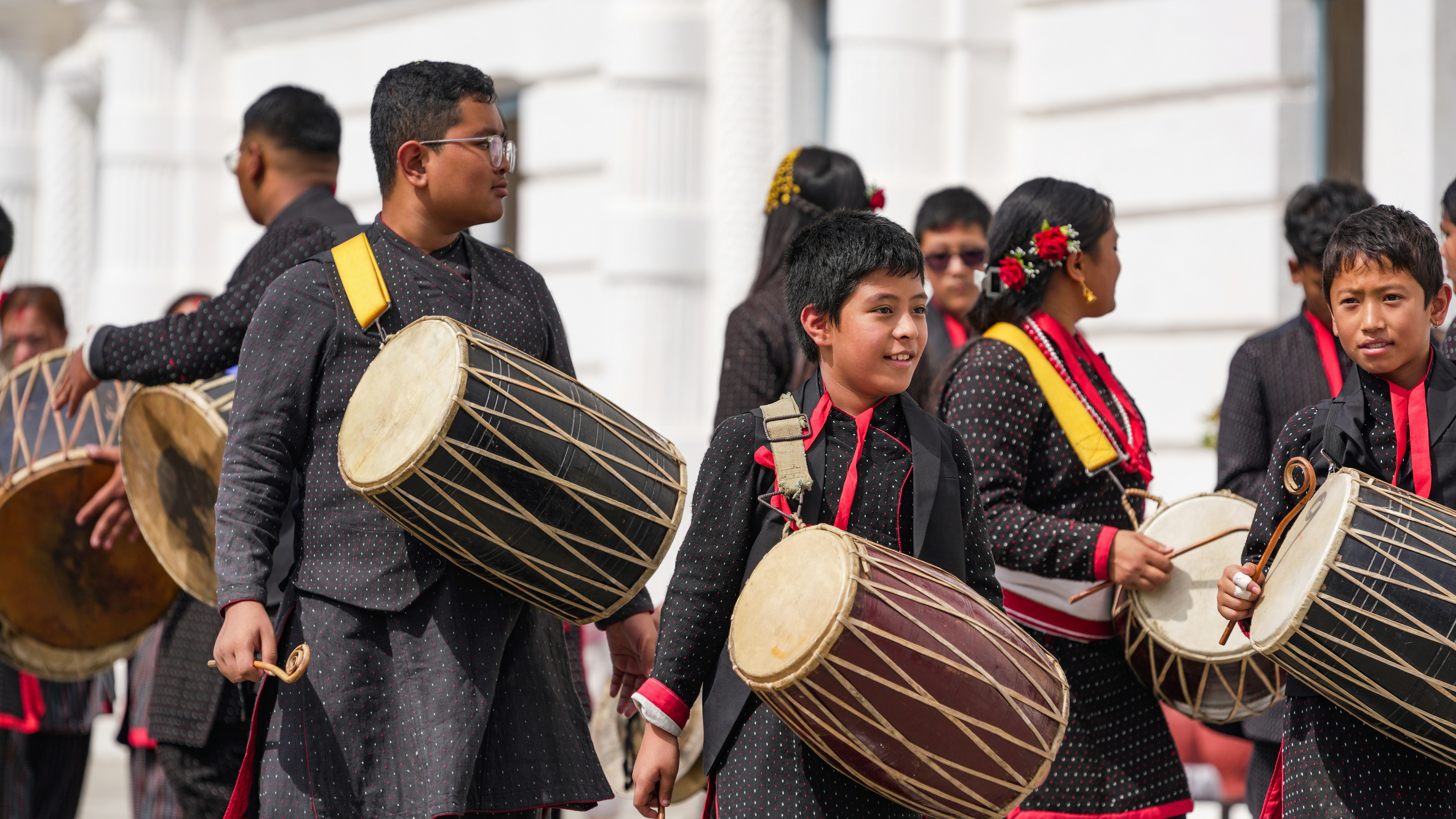 Group of people playing traditional drums outdoors.