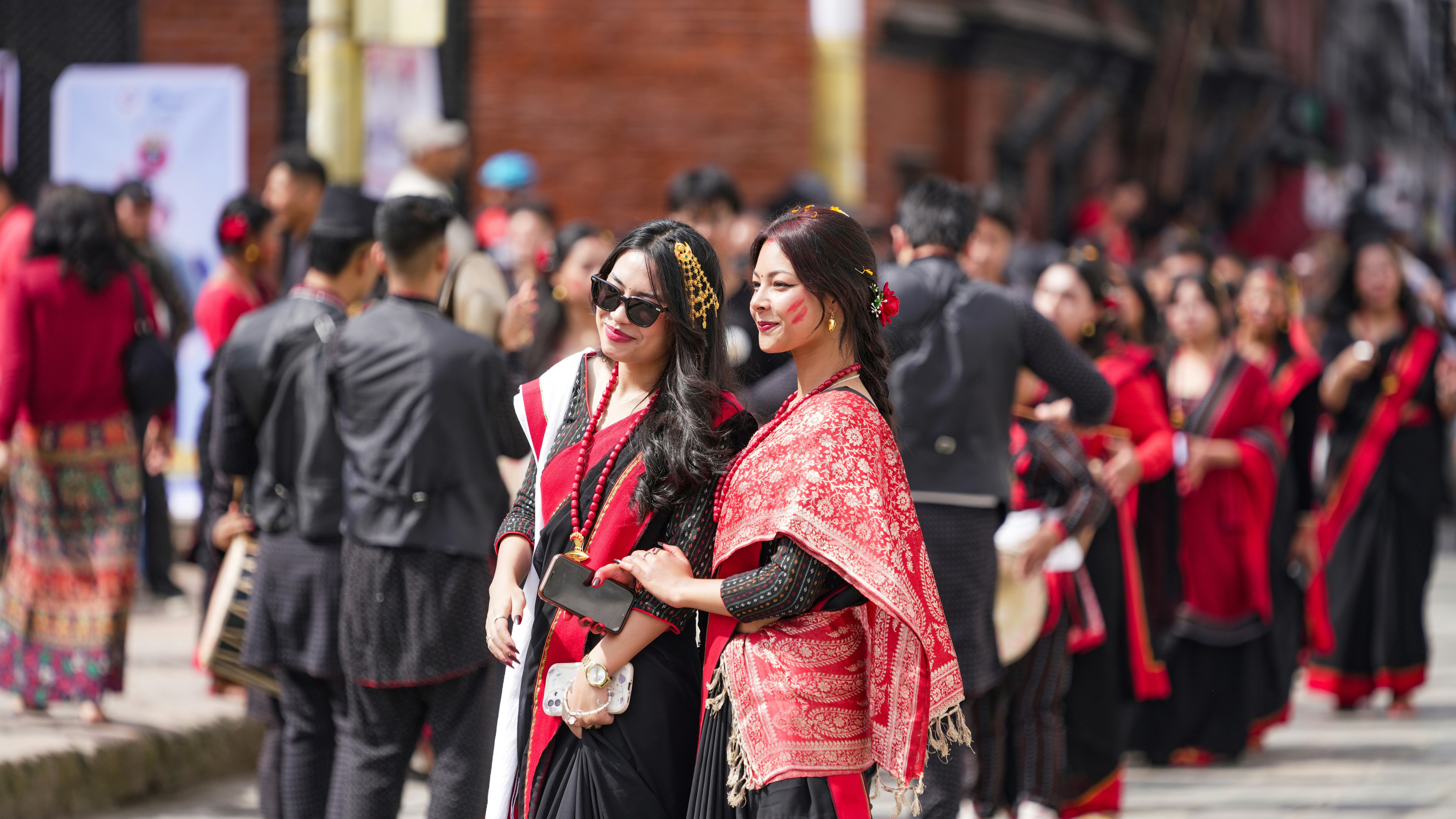 Two women in traditional attire engaged in conversation amidst a lively crowd during a cultural festival.