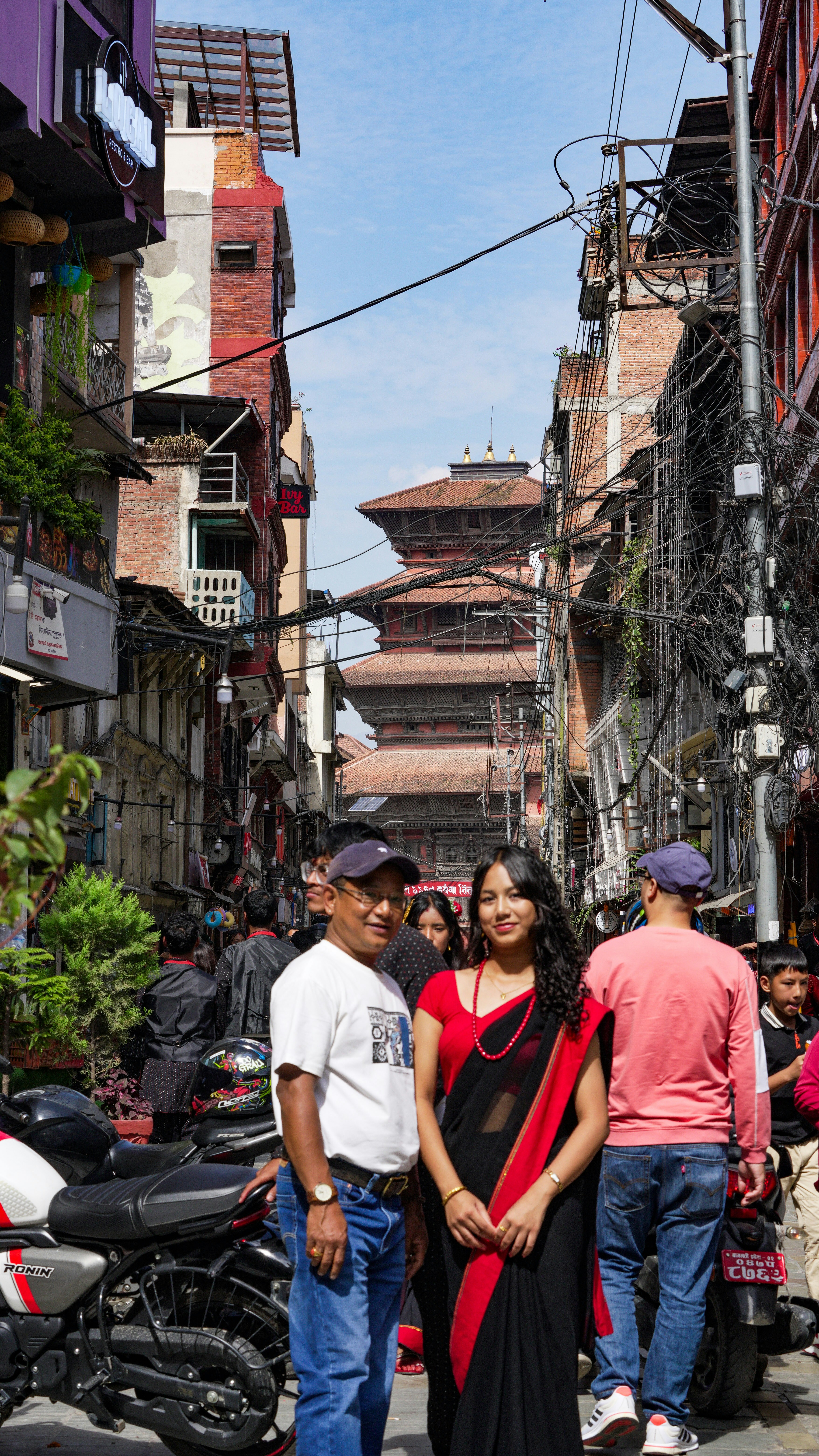 Couple poses in a busy street with traditional architecture.