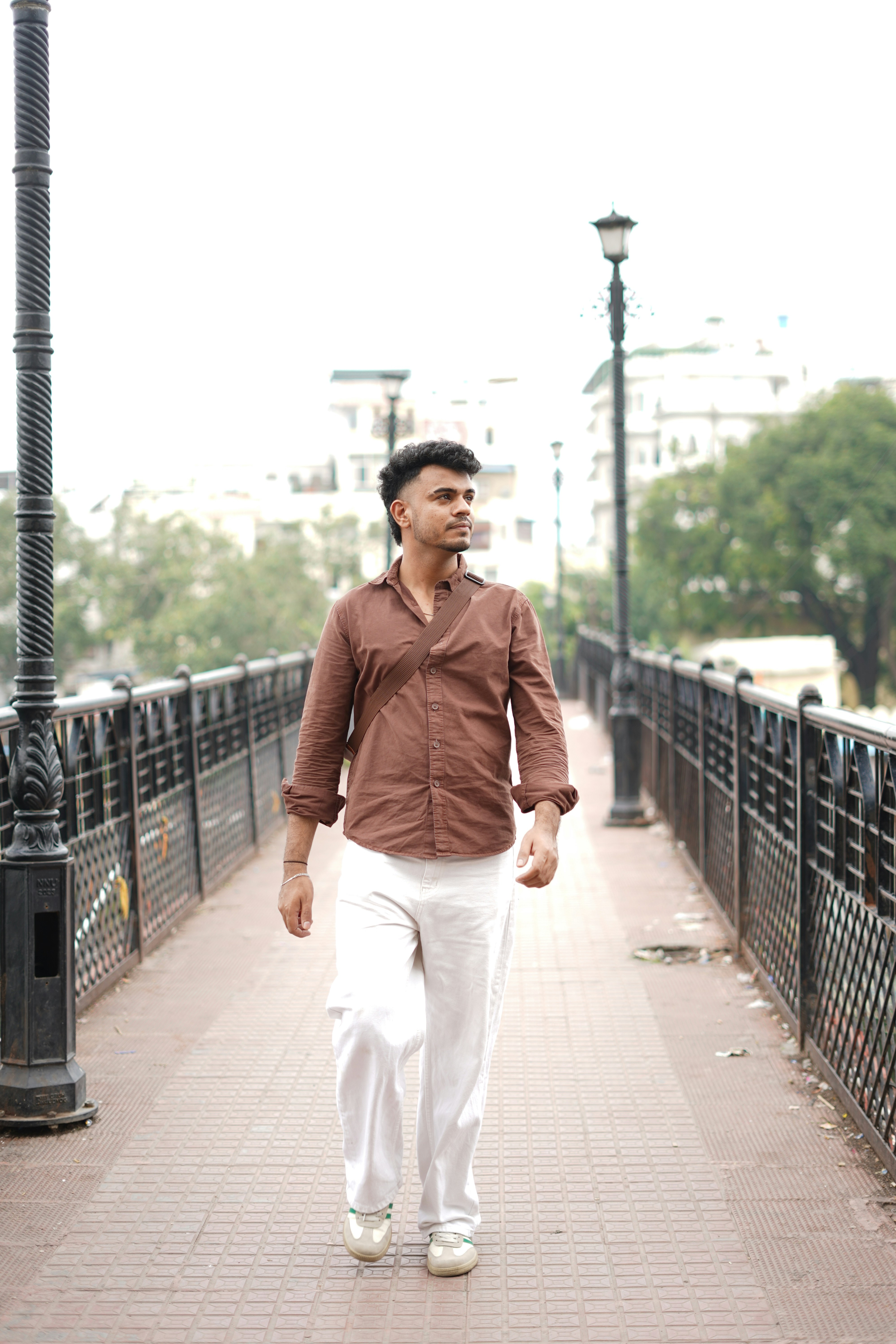 Stride on the Iron Bridge: A Brown-Shirted Traveler against a Misty City Backdrop