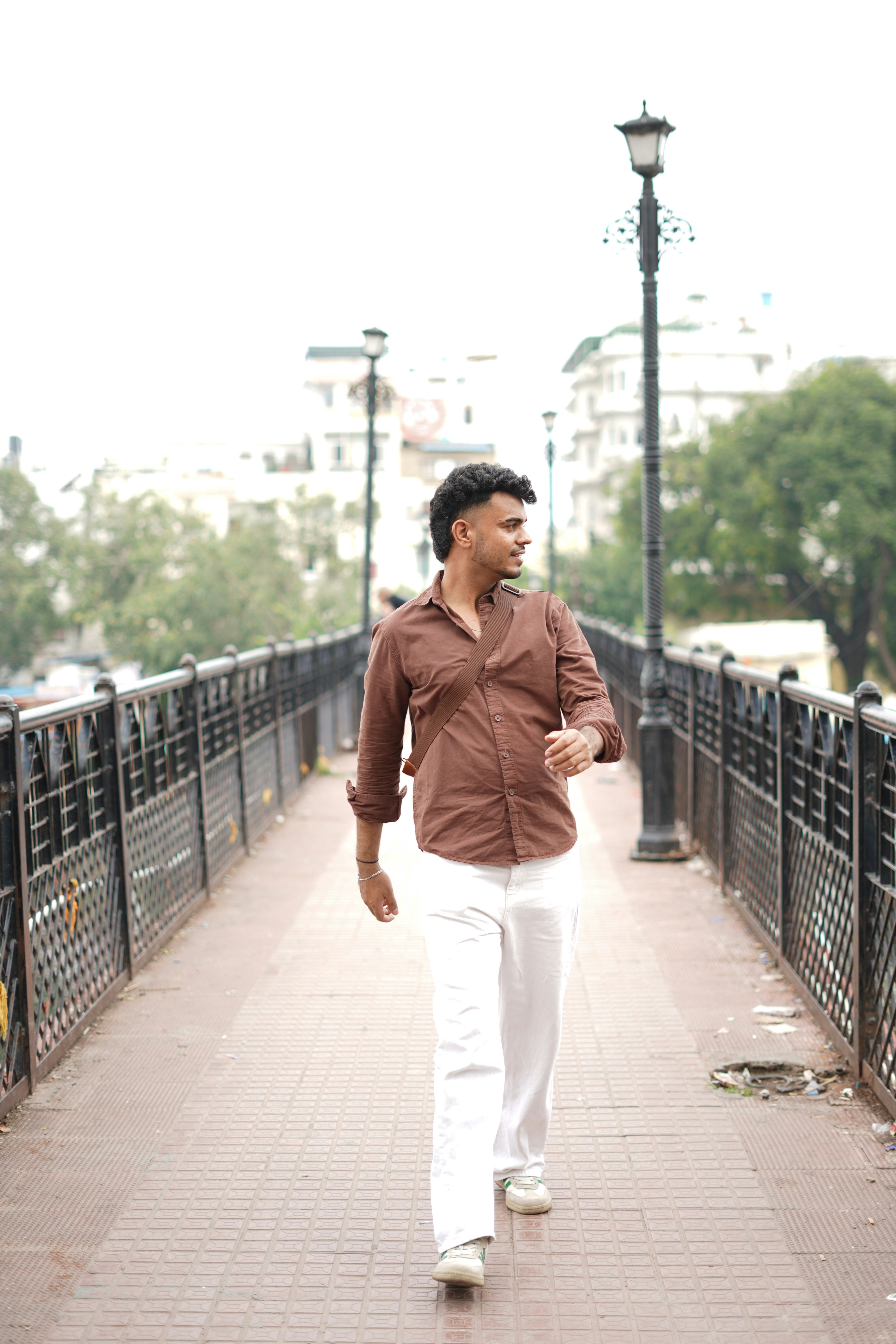 Man walking on a bridge with buildings in background